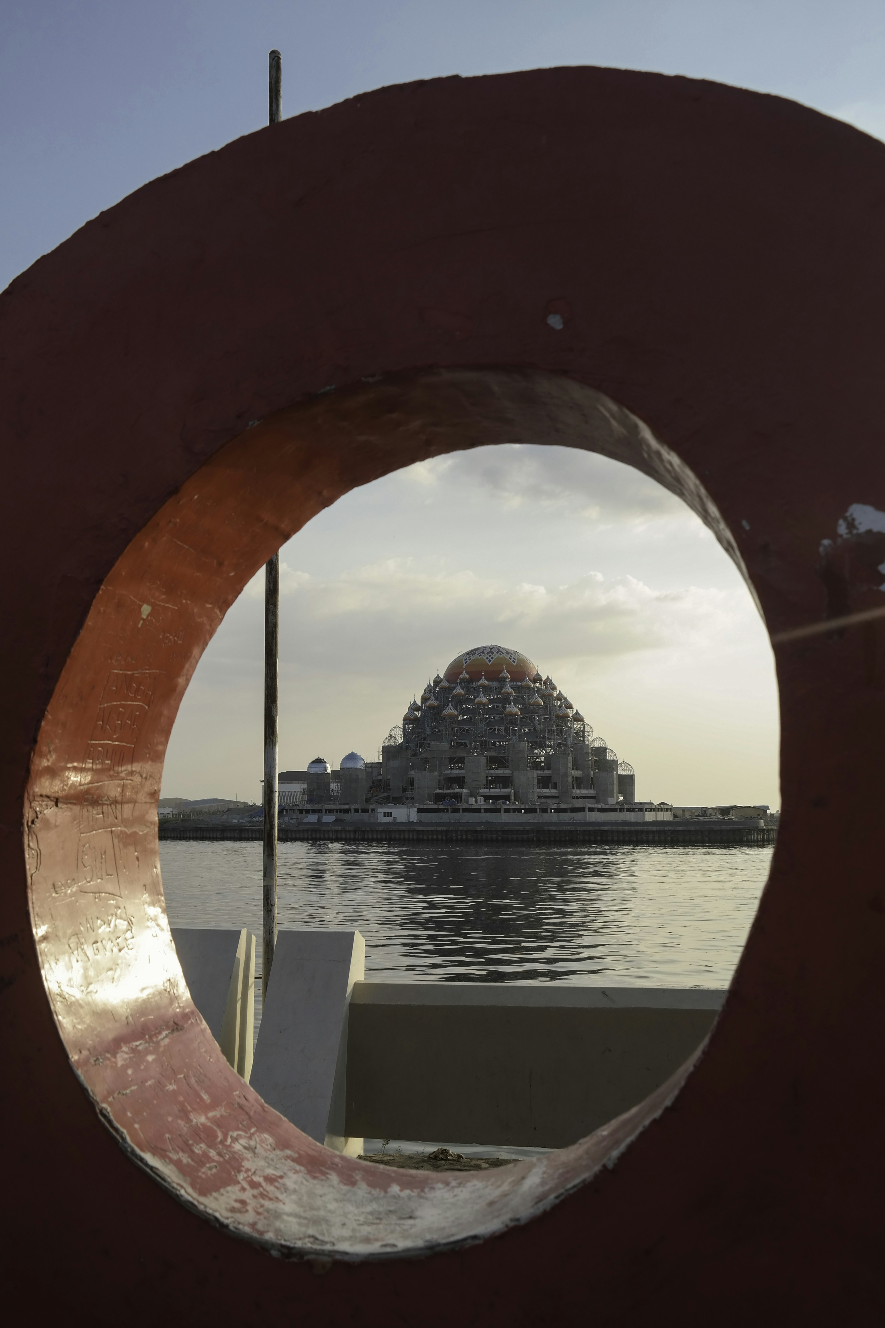 Crimson Ring Framing a Distant Dome Across Quiet Waters