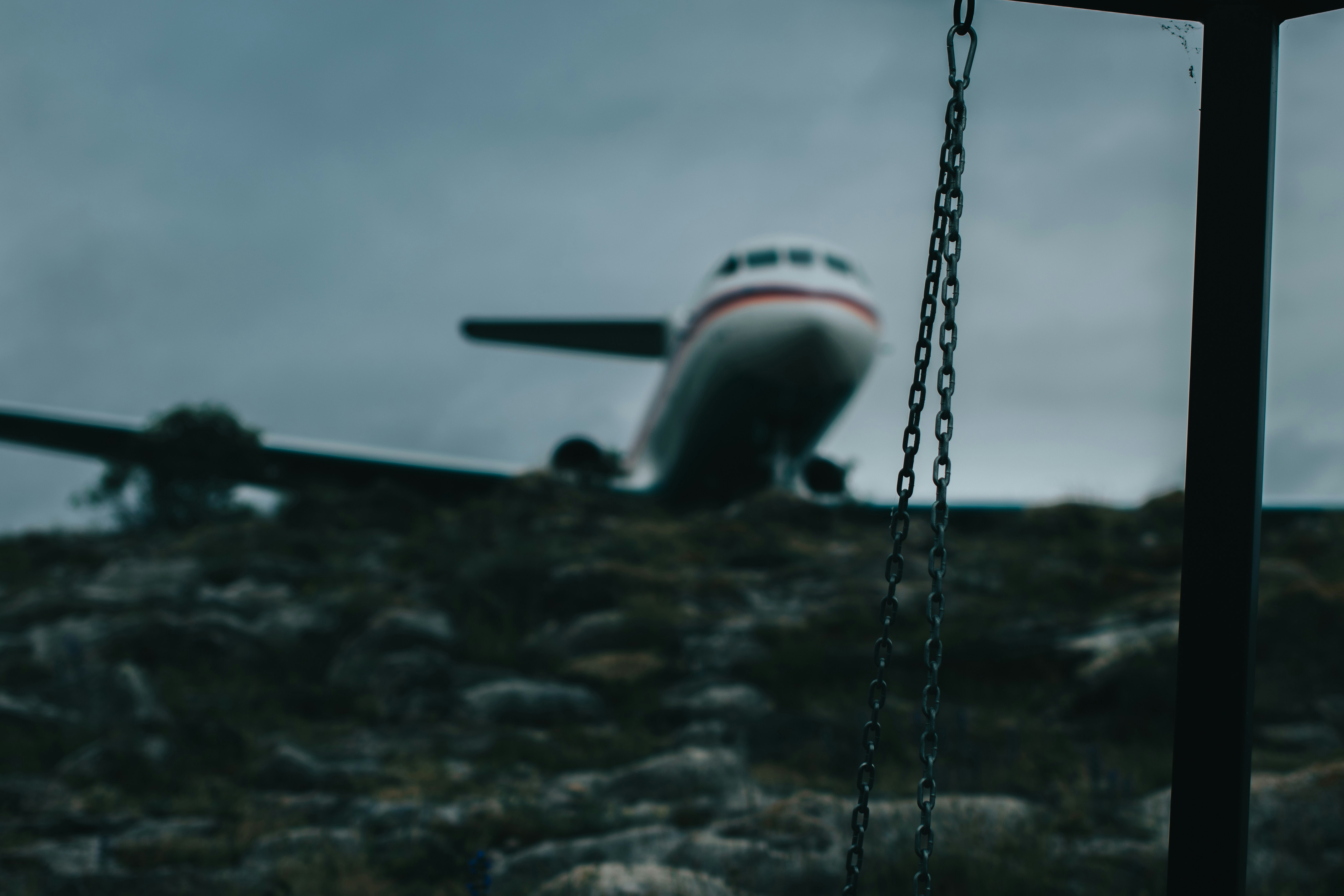 Chain-Framed Distant Airliner in Moody Light