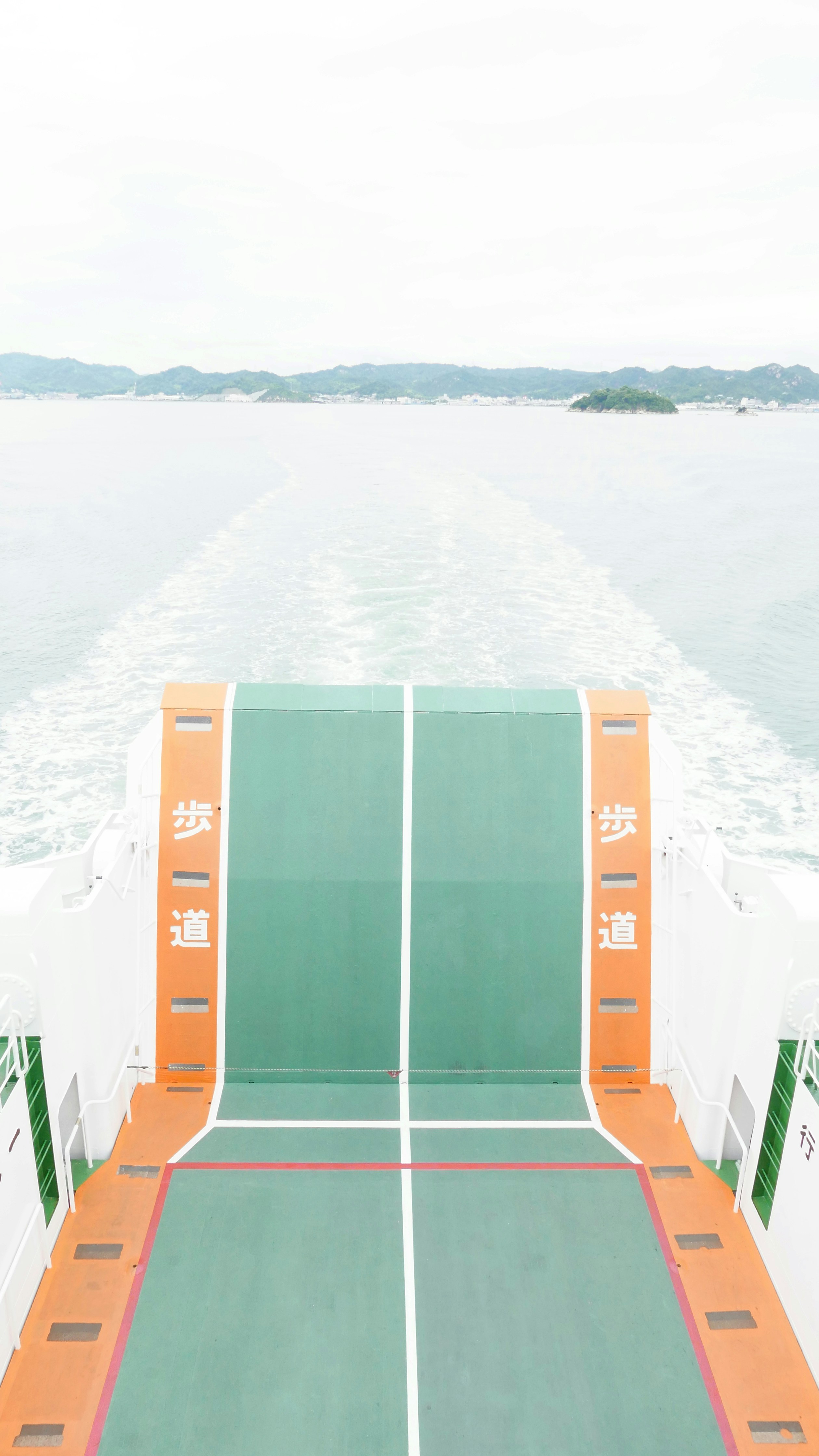 View from the deck of a ferry, showcasing the ramp leading into the water and the serene landscape in the distance. The scene conveys a sense of adventure and exploration.