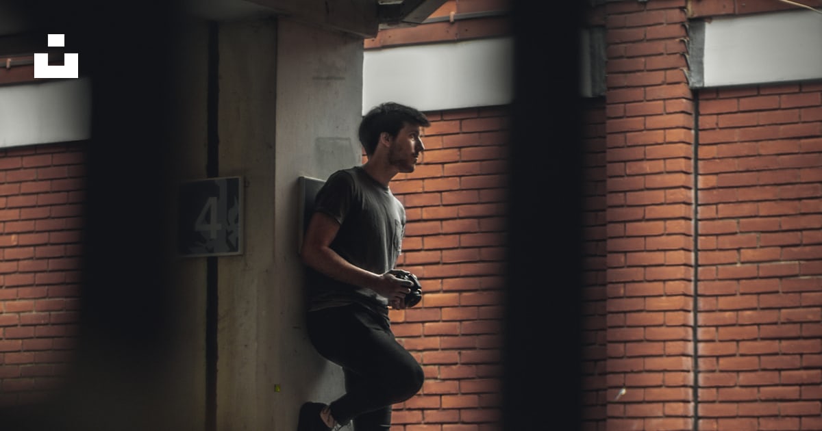 Man In White T Shirt And Black Pants Standing Beside Window Photo
