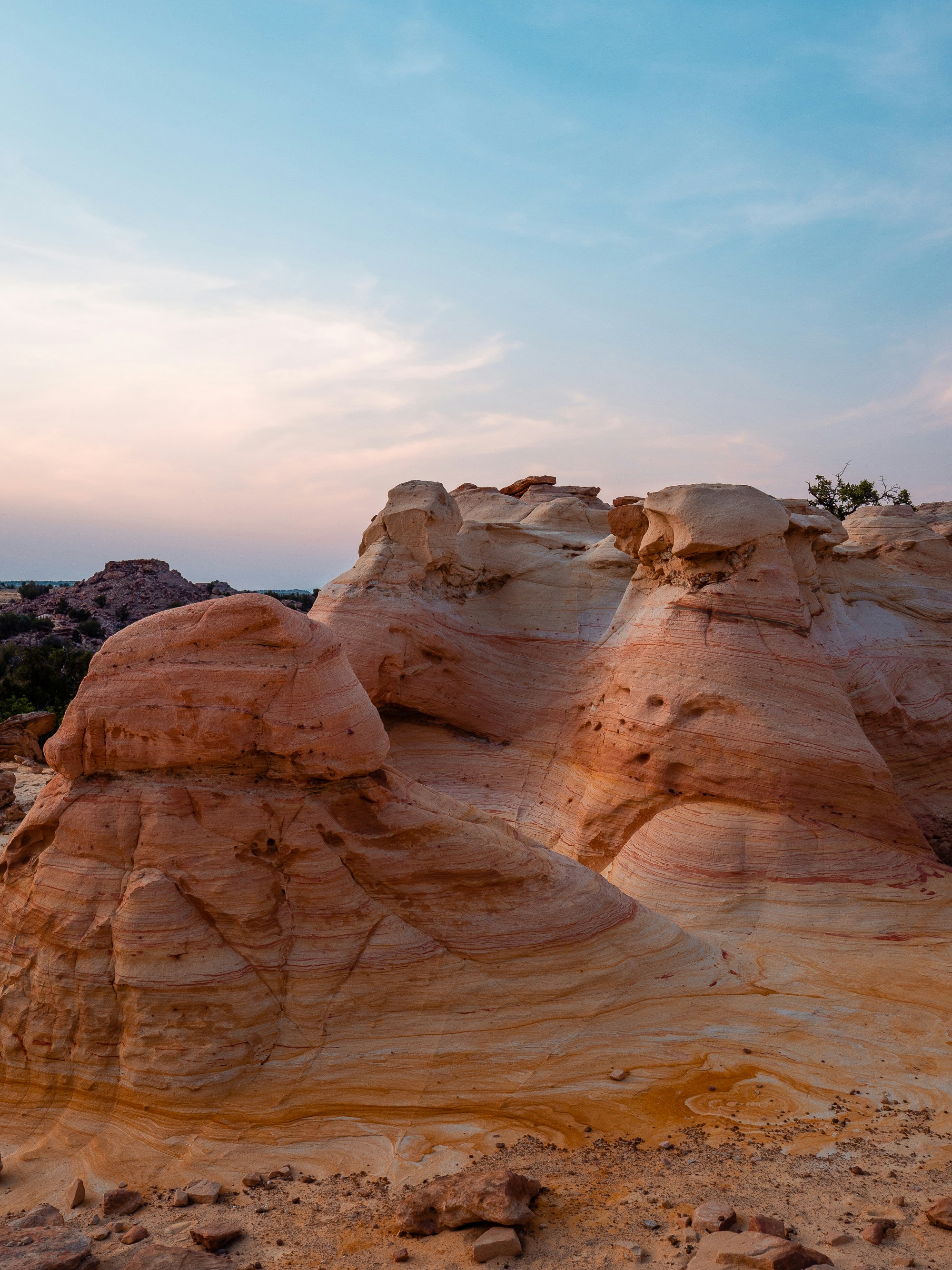 Layers of sandstone formations bathed in soft twilight hues, showcasing the geological artistry of nature. The scene captures the intricate textures and colors of the rocks.