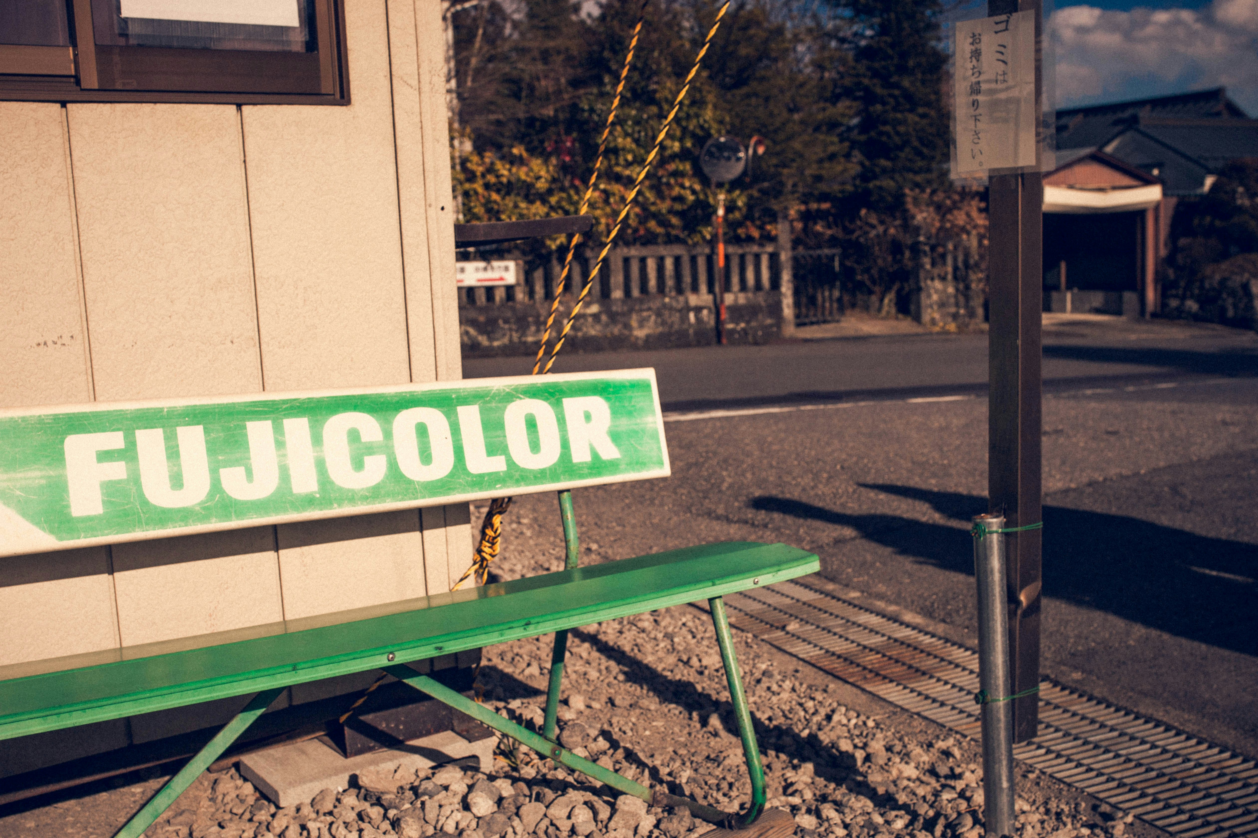 FujiSign on a Quiet Platform: A Green Bench in Late Afternoon Light
