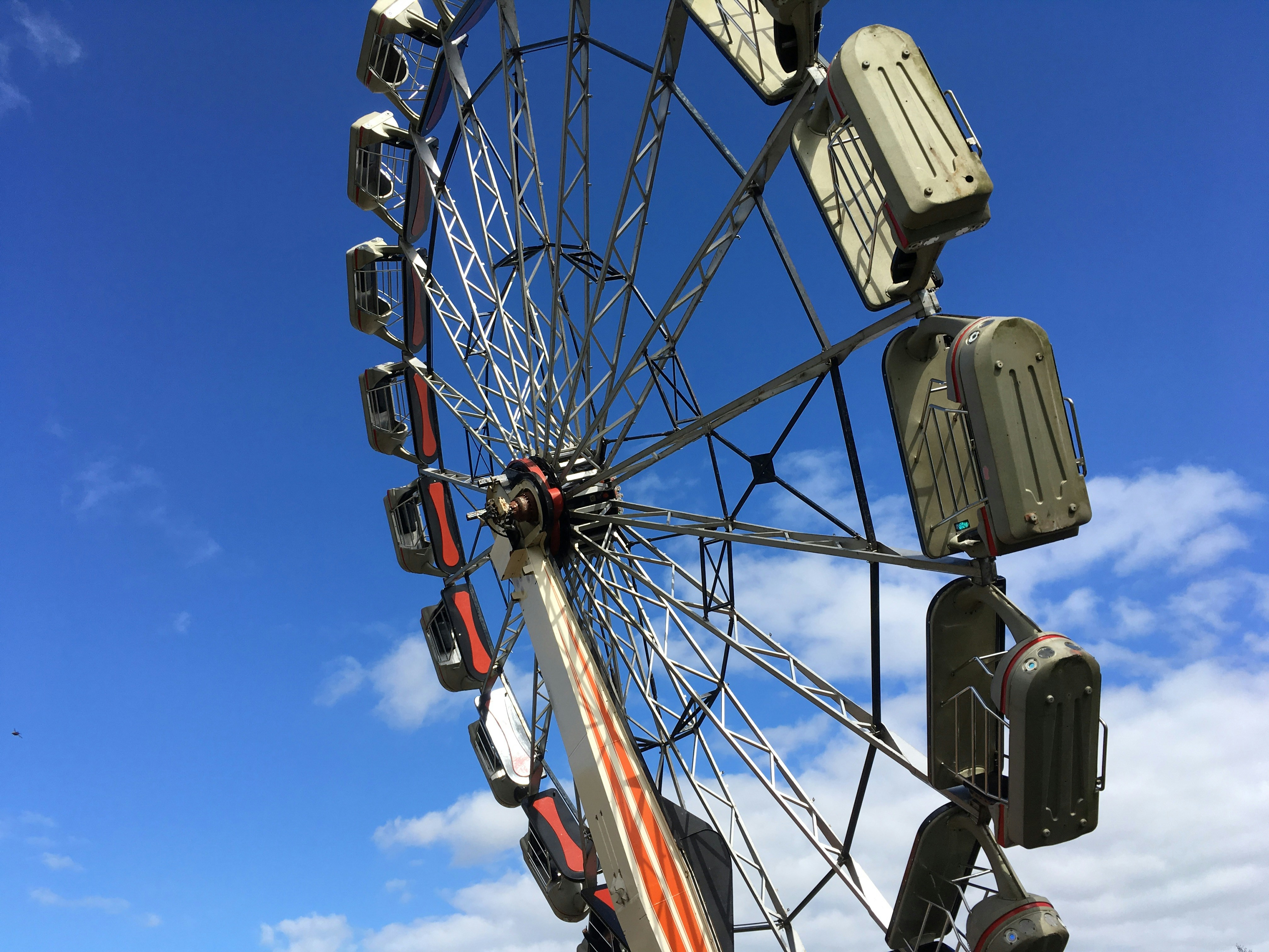 A towering Ferris wheel spins against a vibrant blue sky, showcasing its intricate framework and passenger cabins.