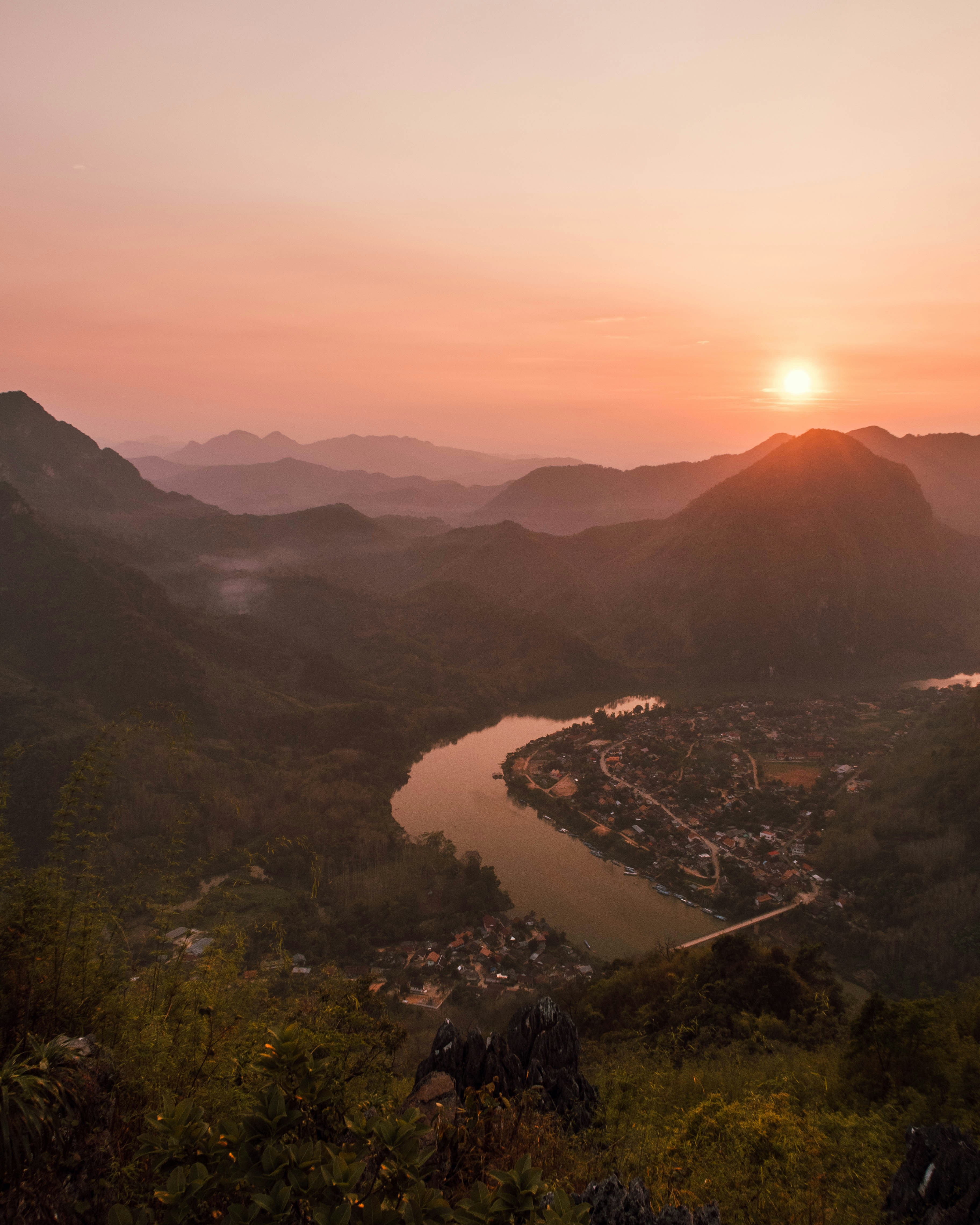 Sunset from a viewpoint overlooking Nong Khiaw, Laos. | aerial view of green trees and mountains during daytime