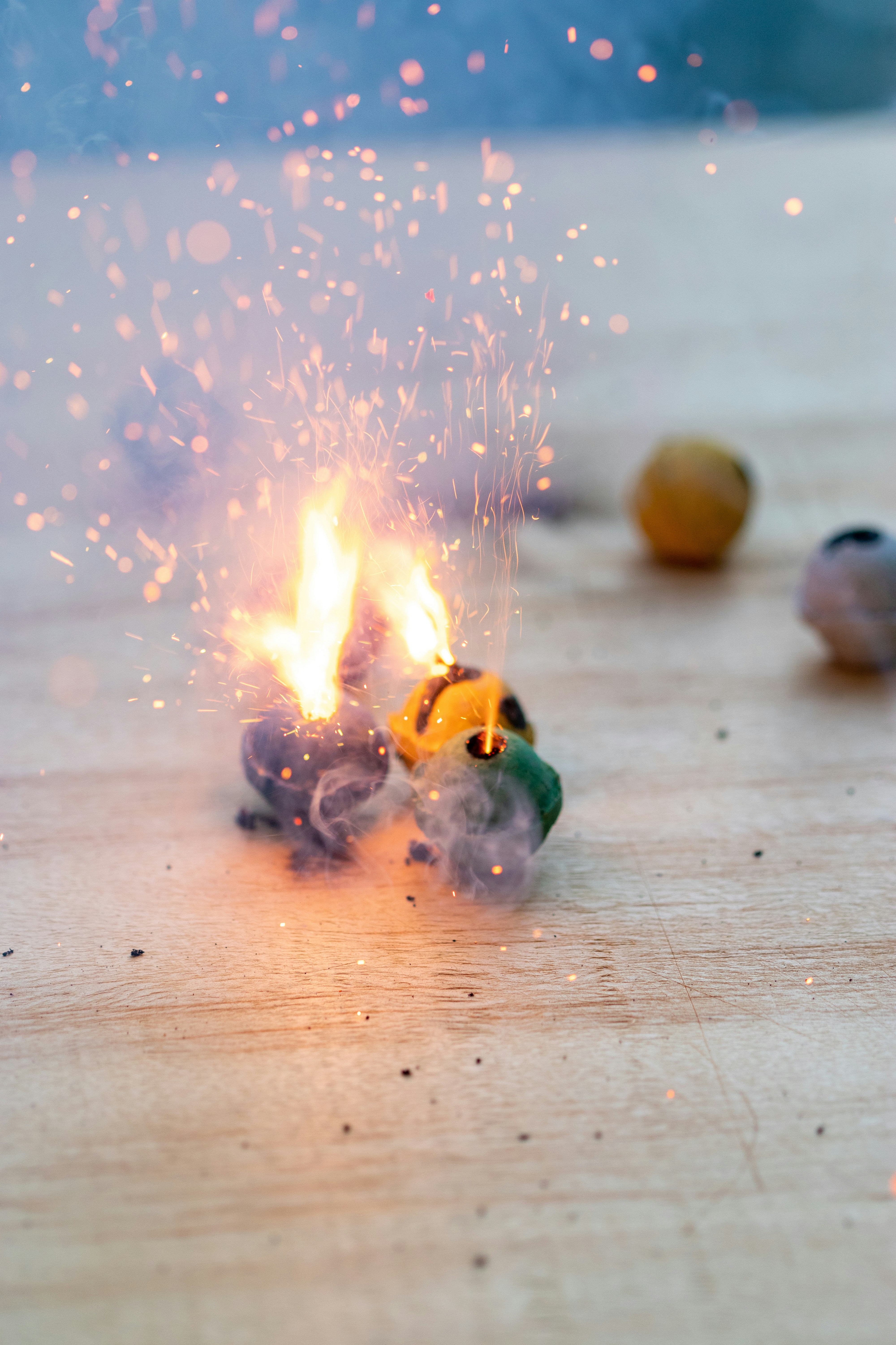 Colorful objects igniting with flames and sparks on a wooden surface, capturing the moment of combustion.
