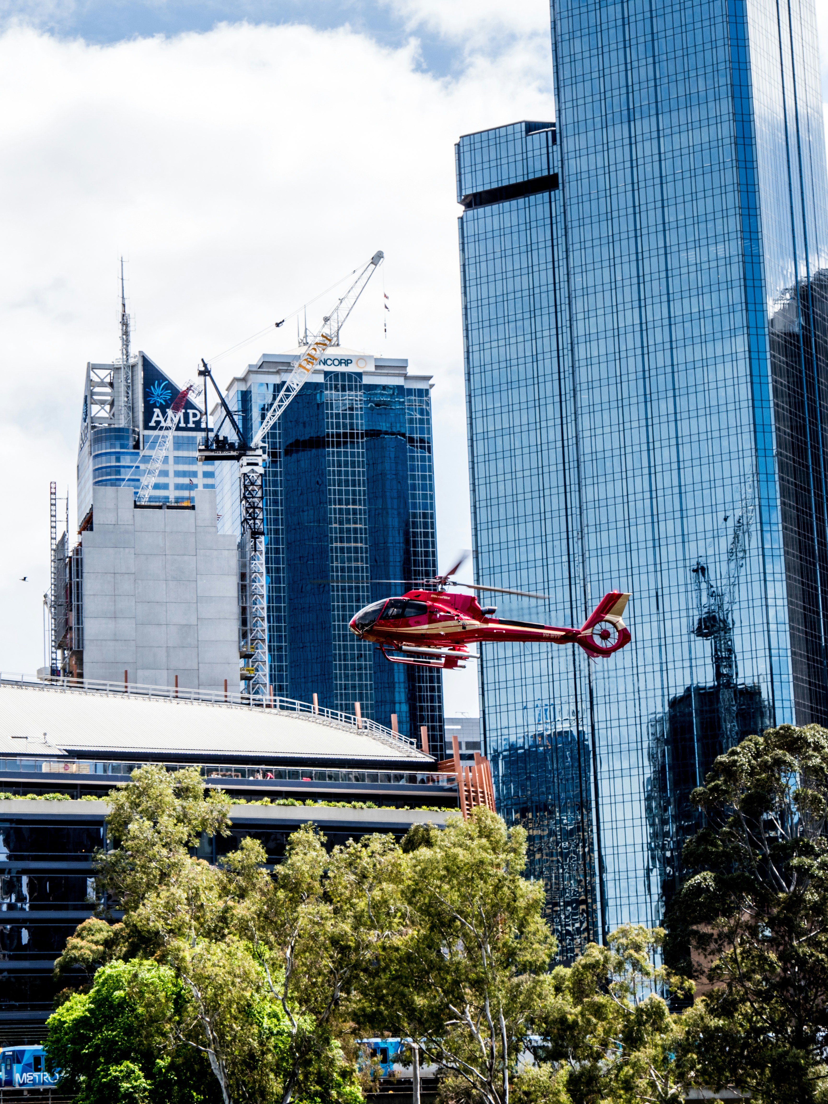 Red Helix over Glass and Greed: A City Helipad in Flight