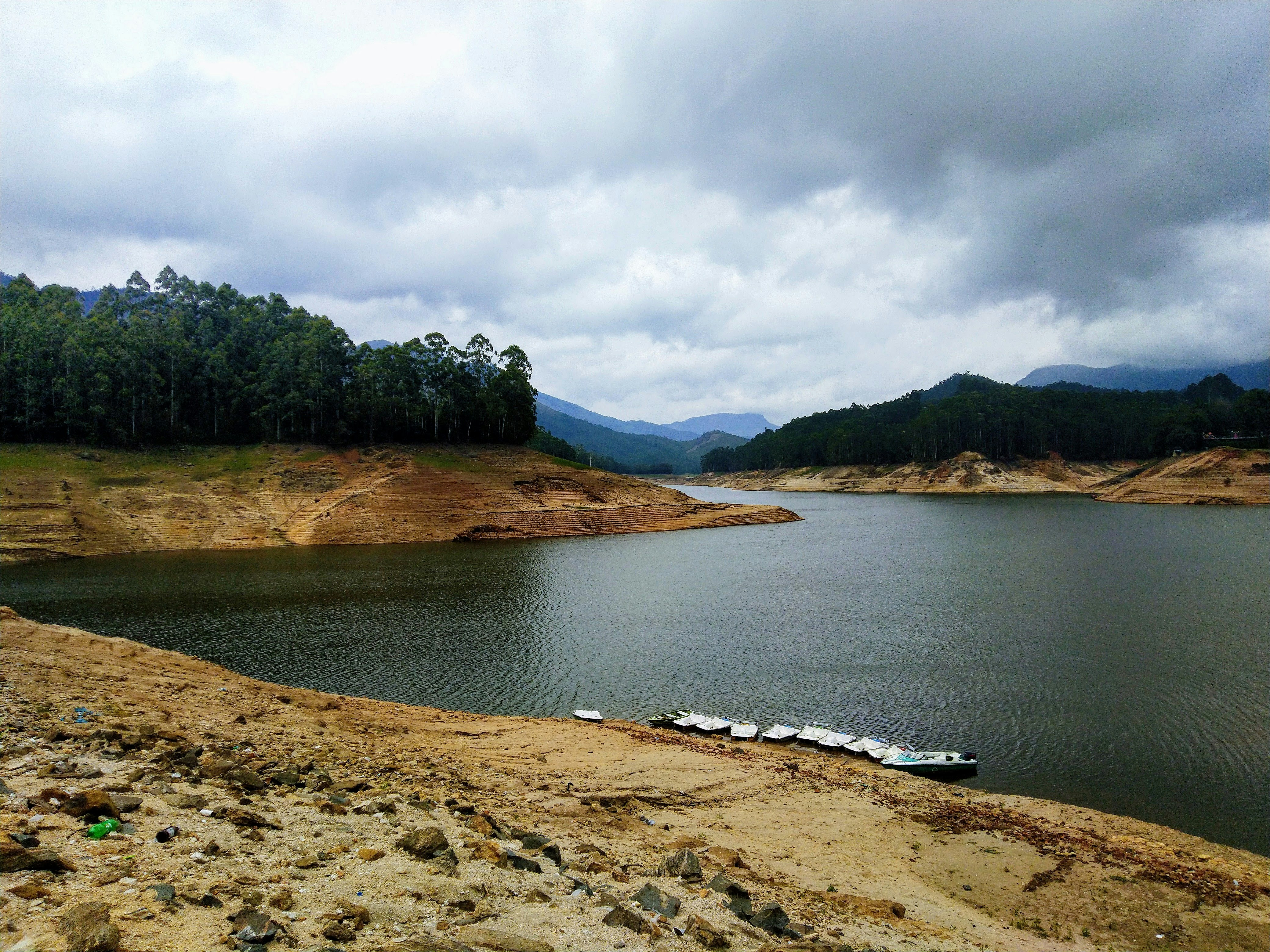 lake surrounded by green trees under white clouds during daytime