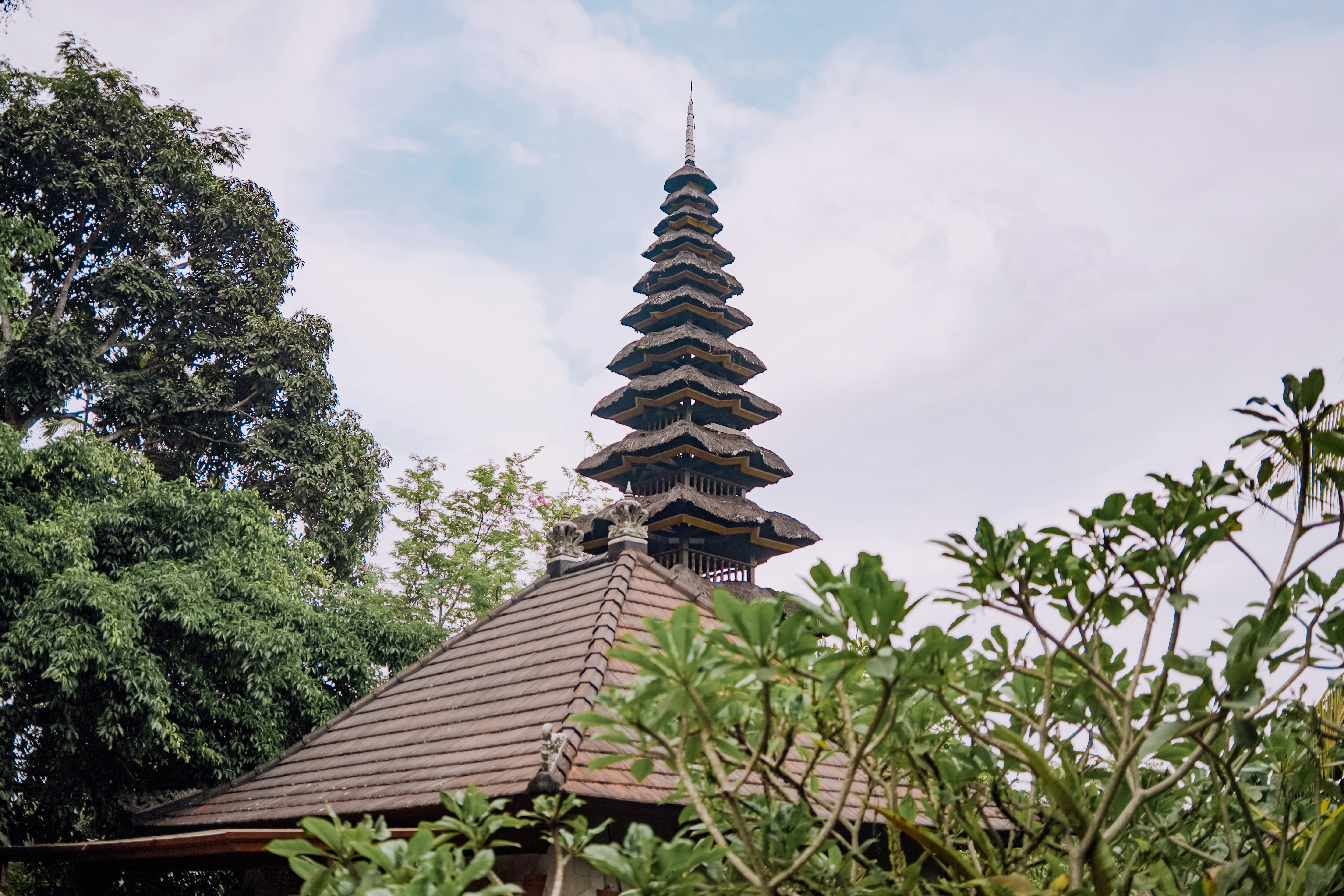 brown and white temple surrounded by green trees under white clouds during daytime