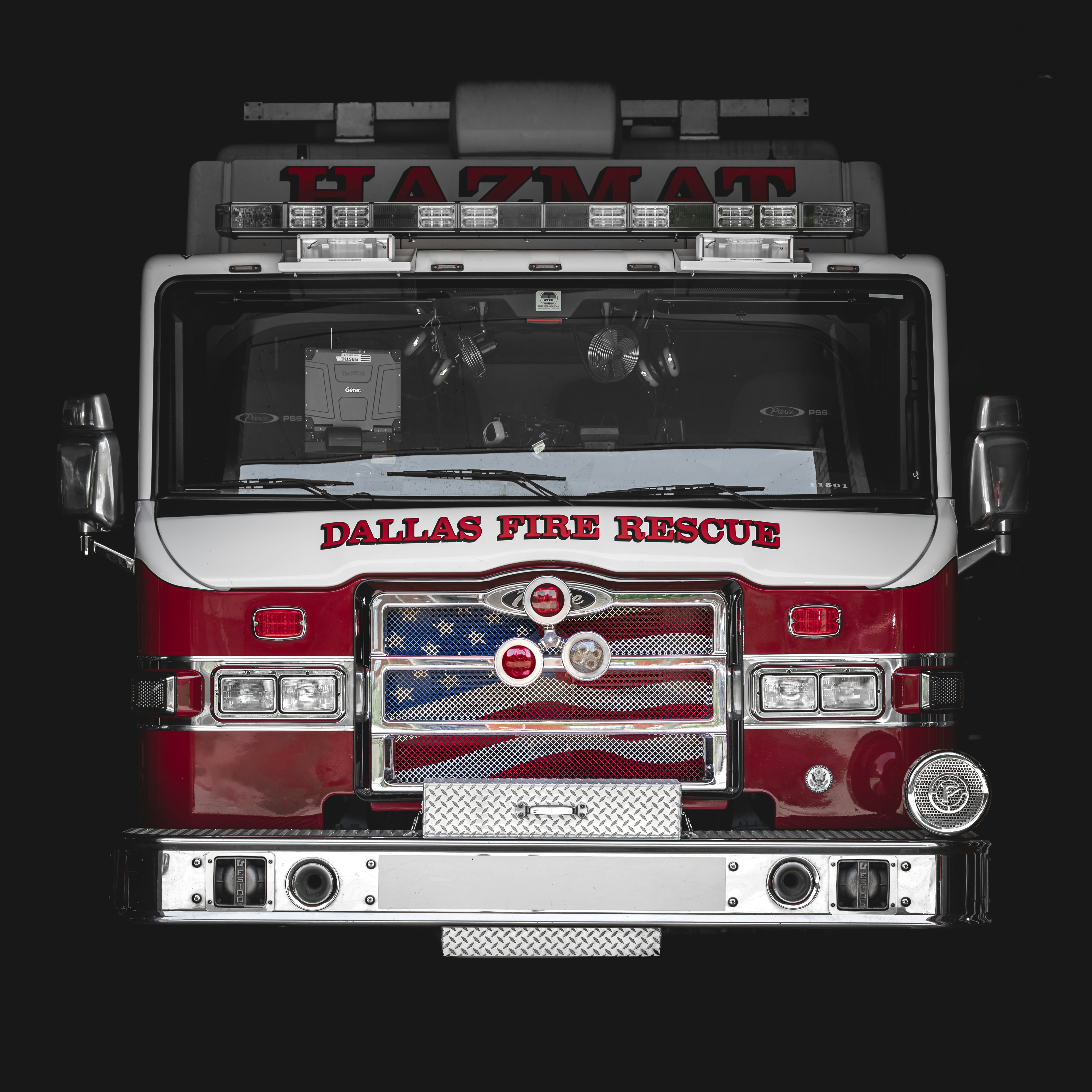 Front view of a Dallas Fire Rescue Hazmat truck, showcasing its striking red and white design against a dark background.