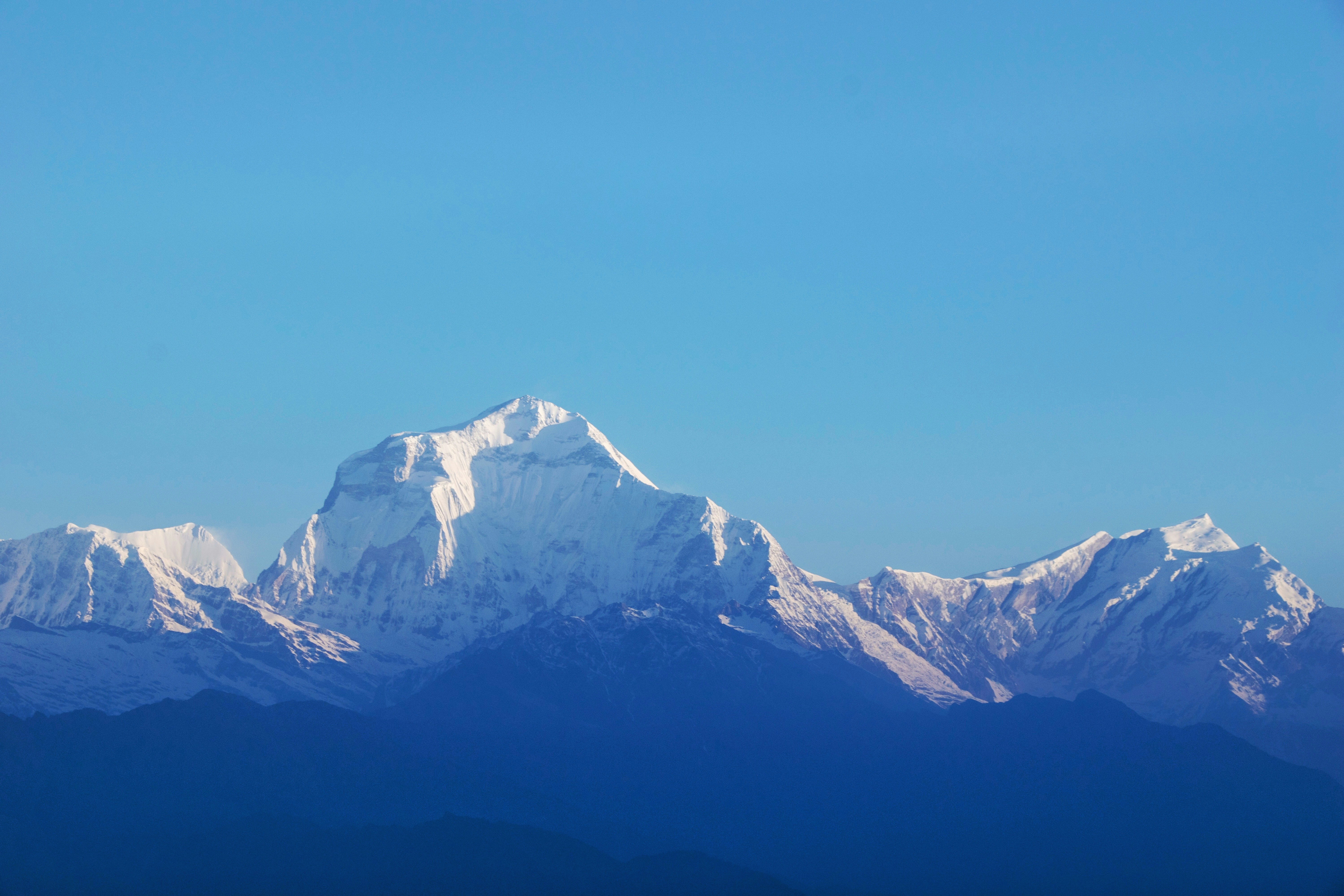 Snow-capped mountain range under a clear blue sky, showcasing the grandeur of nature's heights.