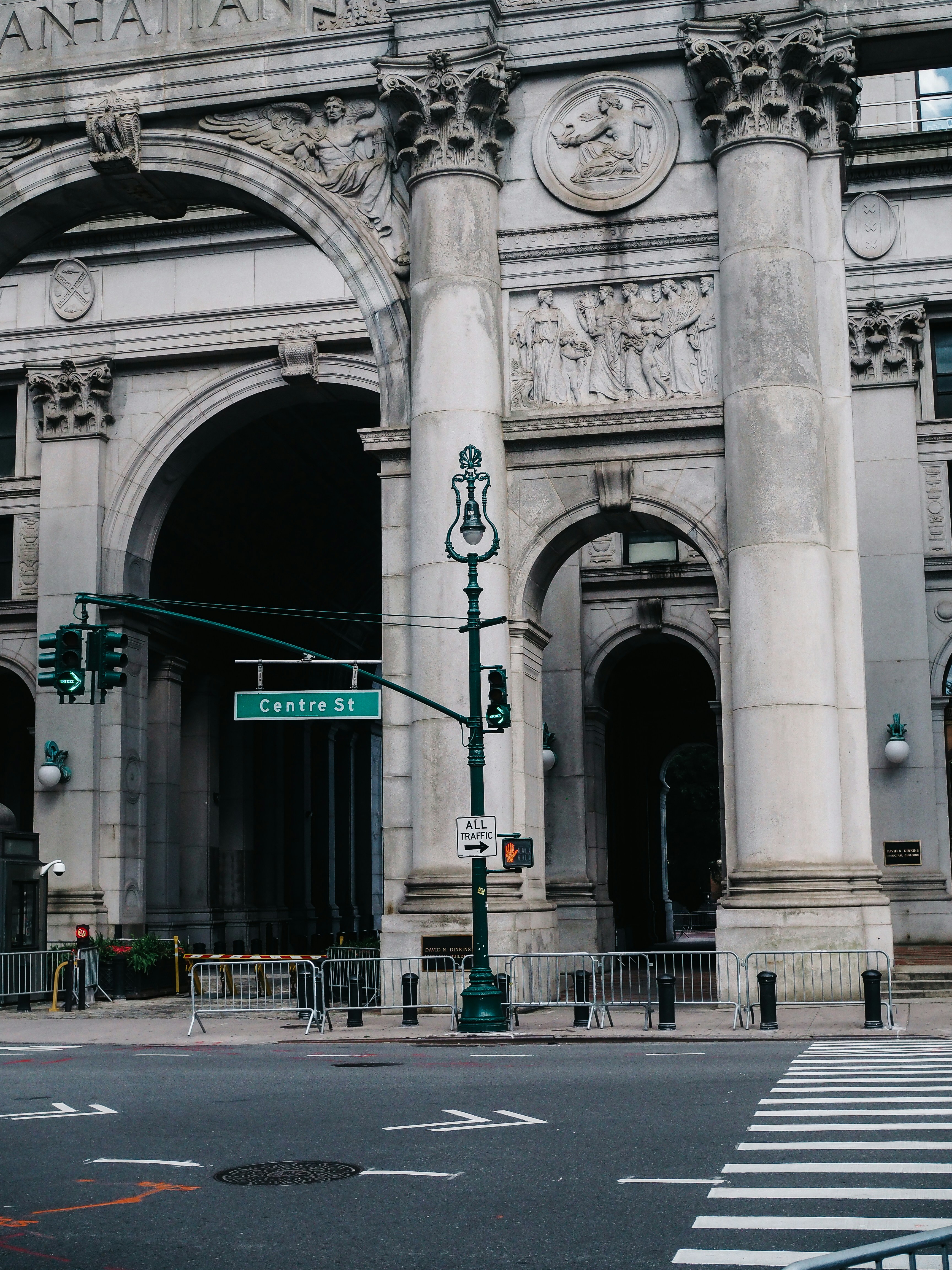 Intricate stonework and grand arches frame the entrance to a historic building, with street signage directing traffic below.