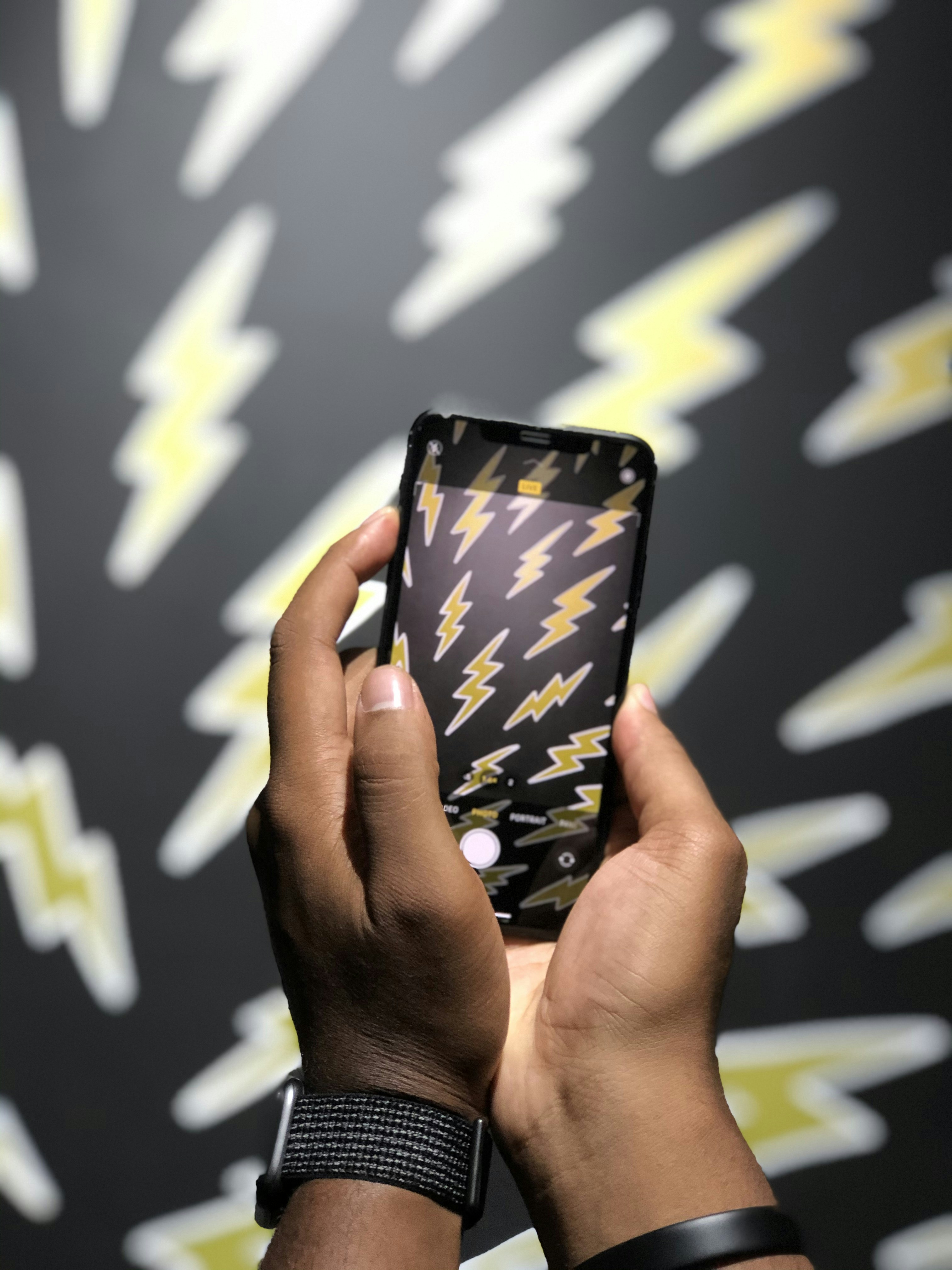 Bolt Echo: Hands Frame a Lightning-Patterned Wall Through a Phone