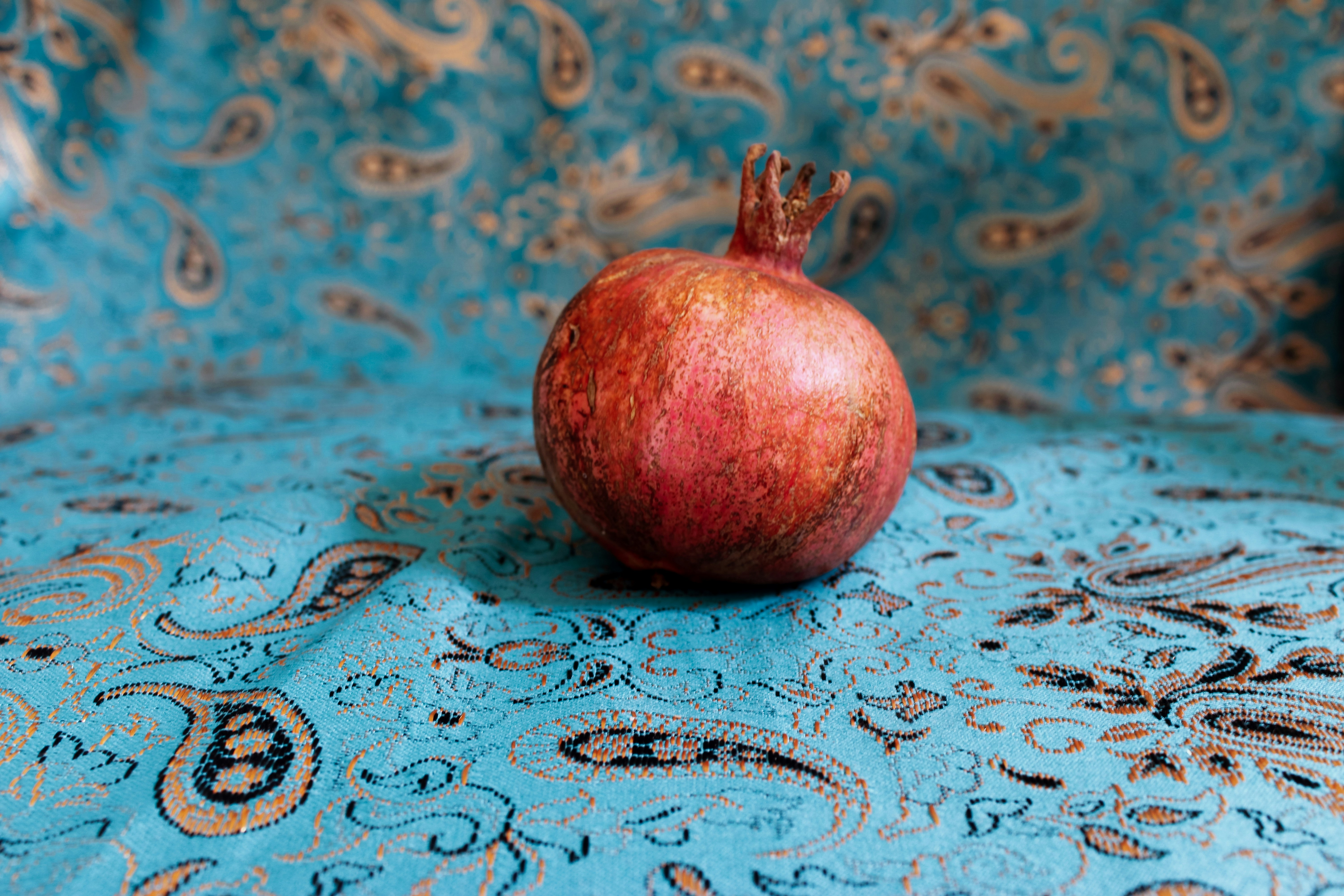Crimson Pomegranate on Turquoise Paisley: A Quiet Study in Texture and Color