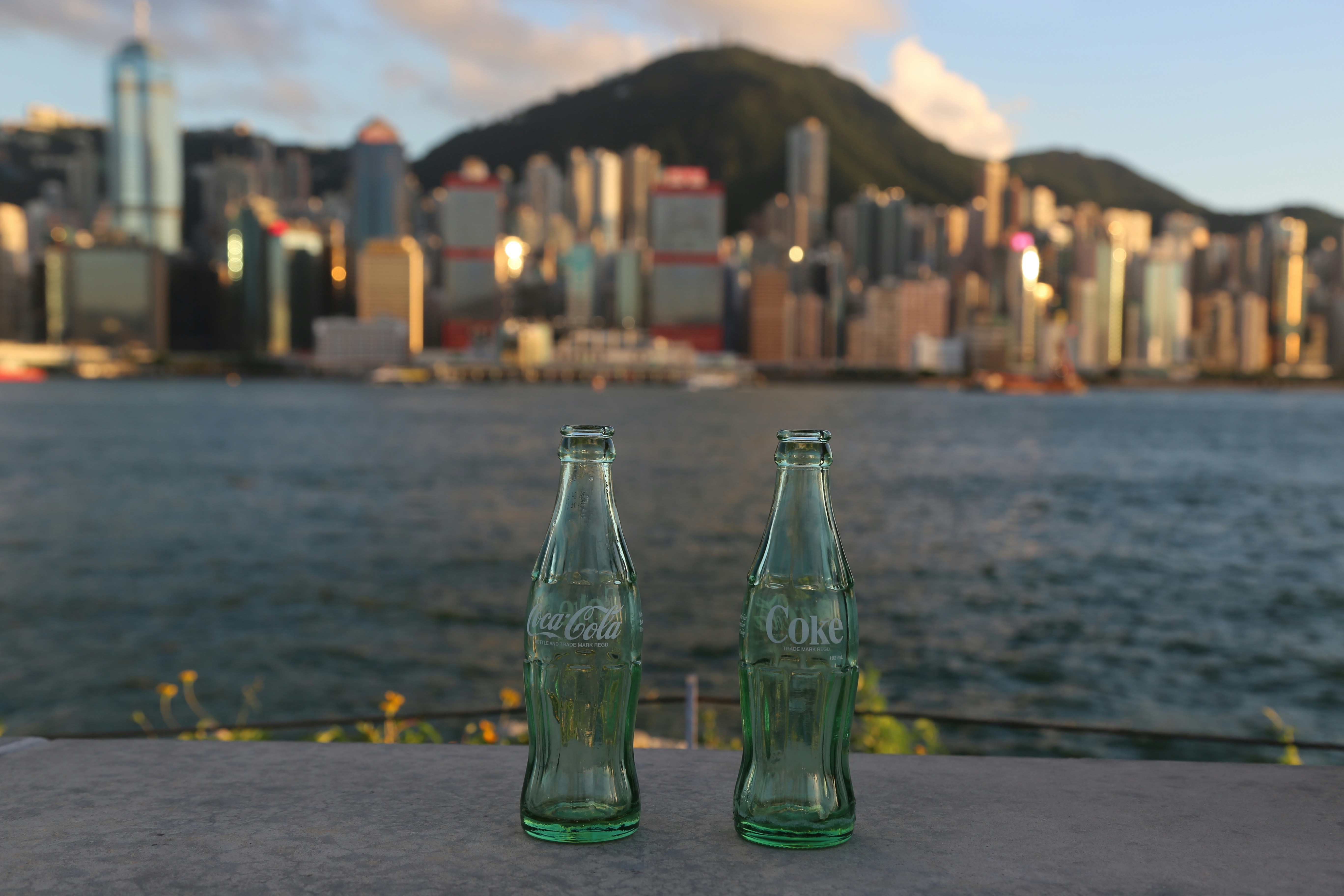 Twin Coke Bottles Framing a Waterfront Skyline at Dusk