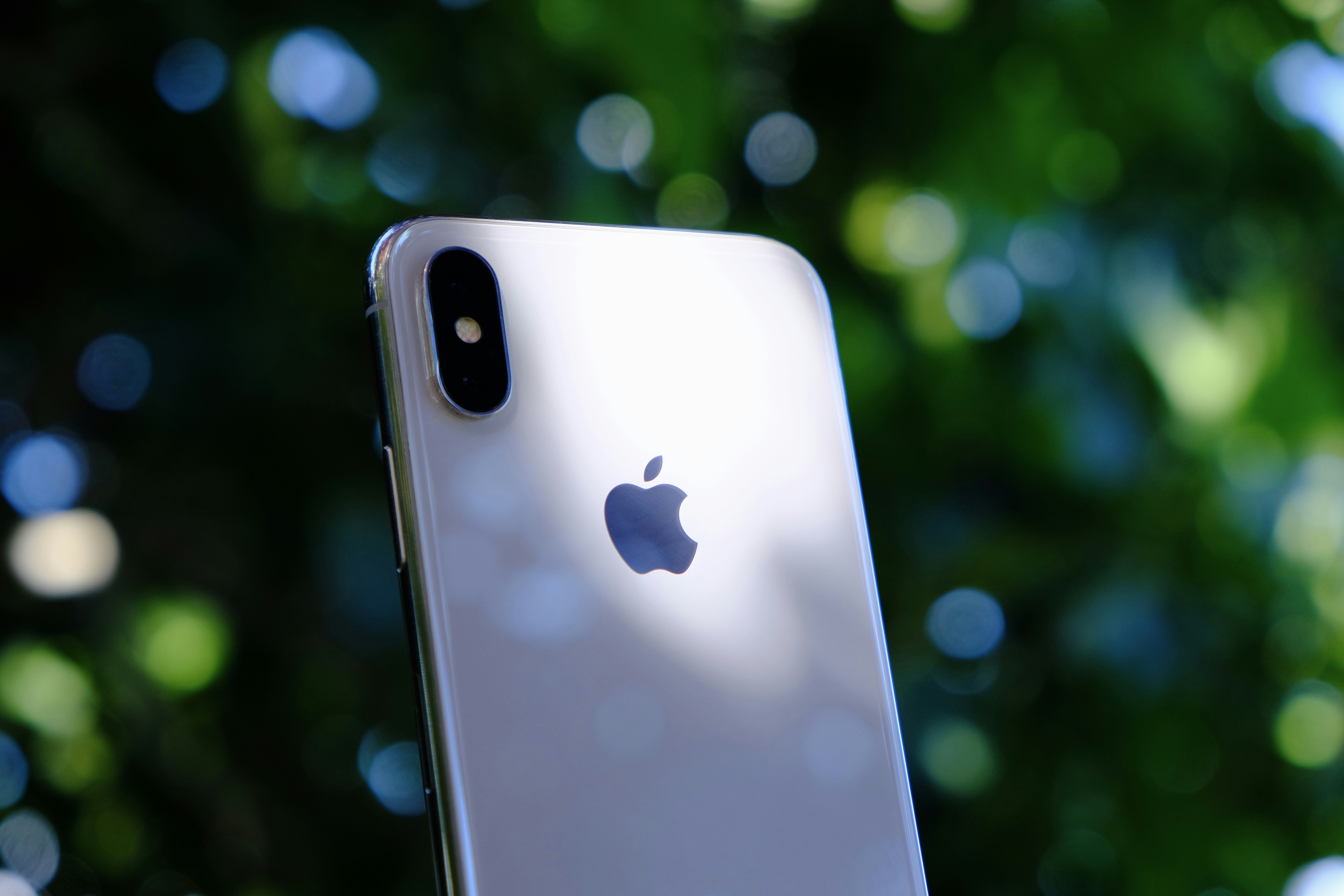 Close-up of an Apple smartphone showcasing its sleek design against a blurred green backdrop.