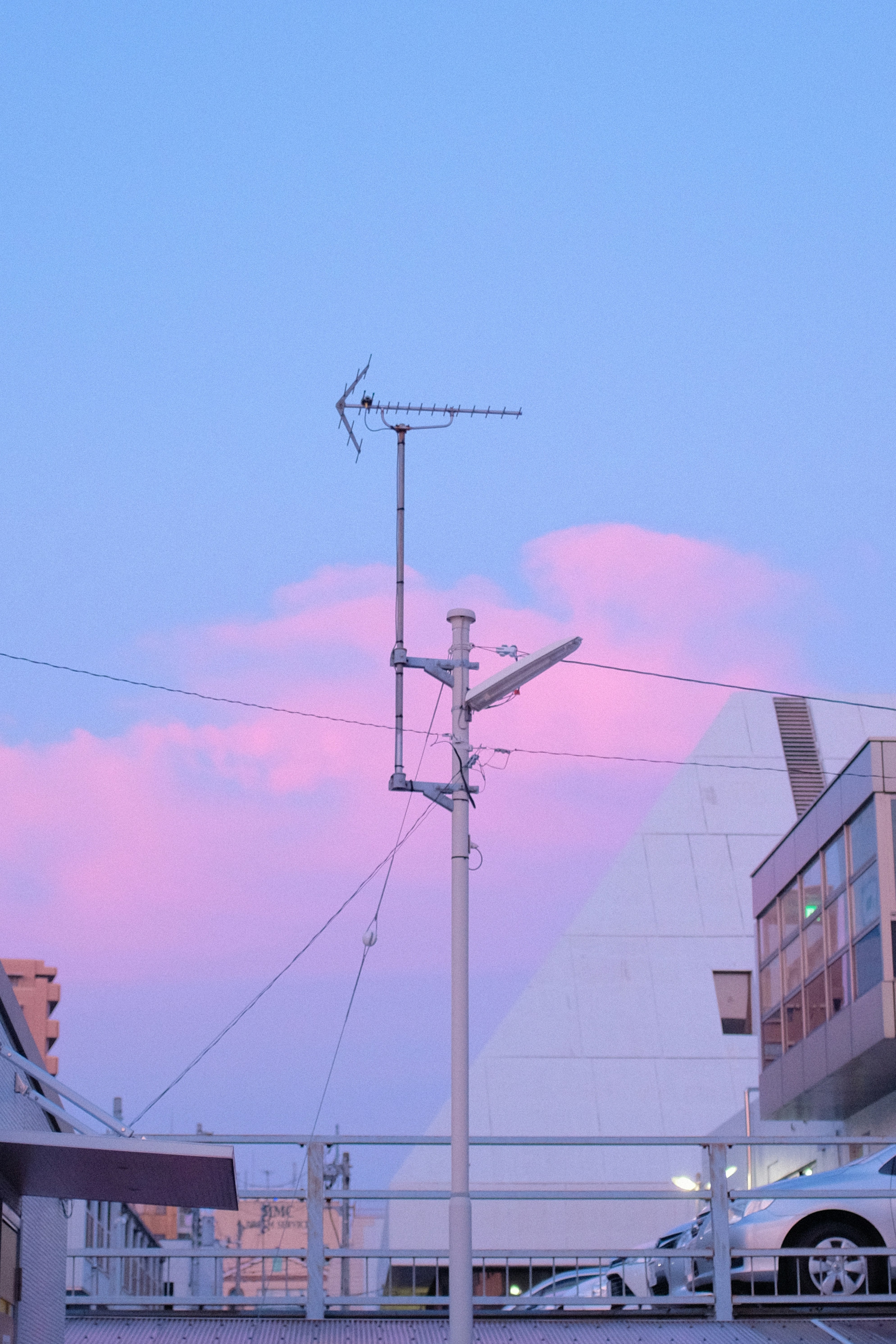 Pink-tinged rooftop antenna under a pastel sky