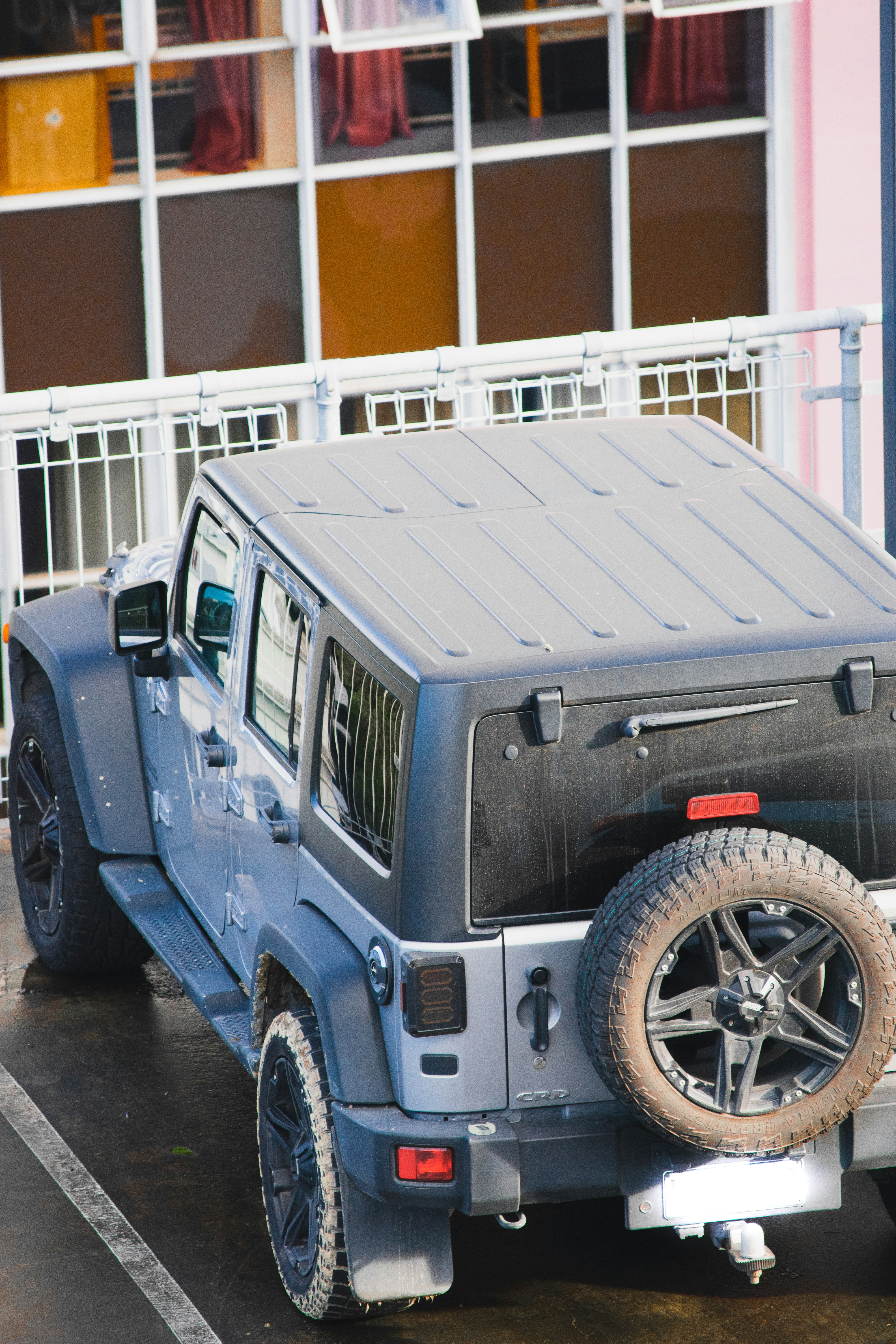 Rain-Slick G-Wagon: Spare Tire and Rugged Silhouette by a Glass Facade