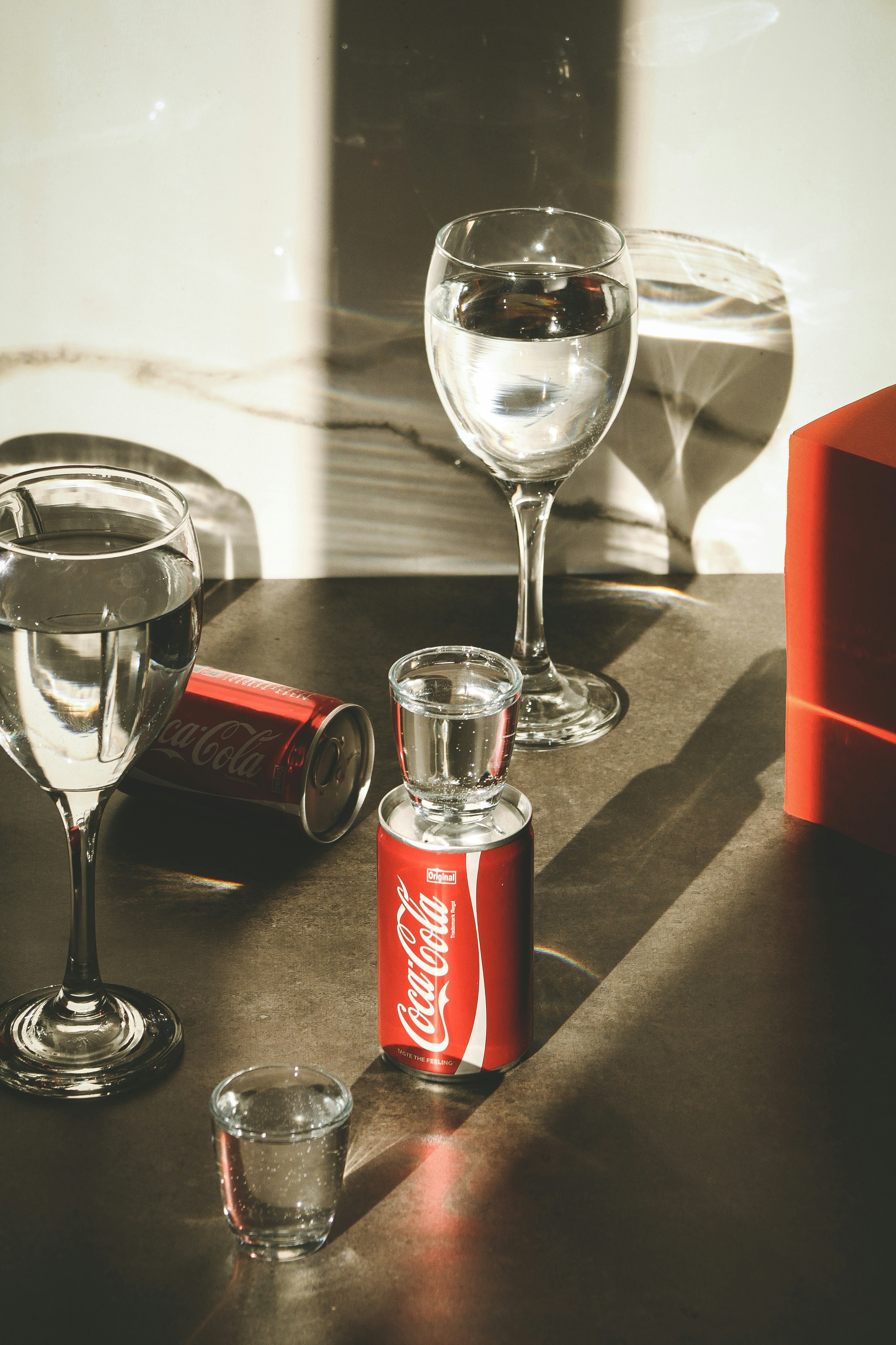 Crimson Coca-Cola Can Surrounded by Glassware in Warm Studio Light