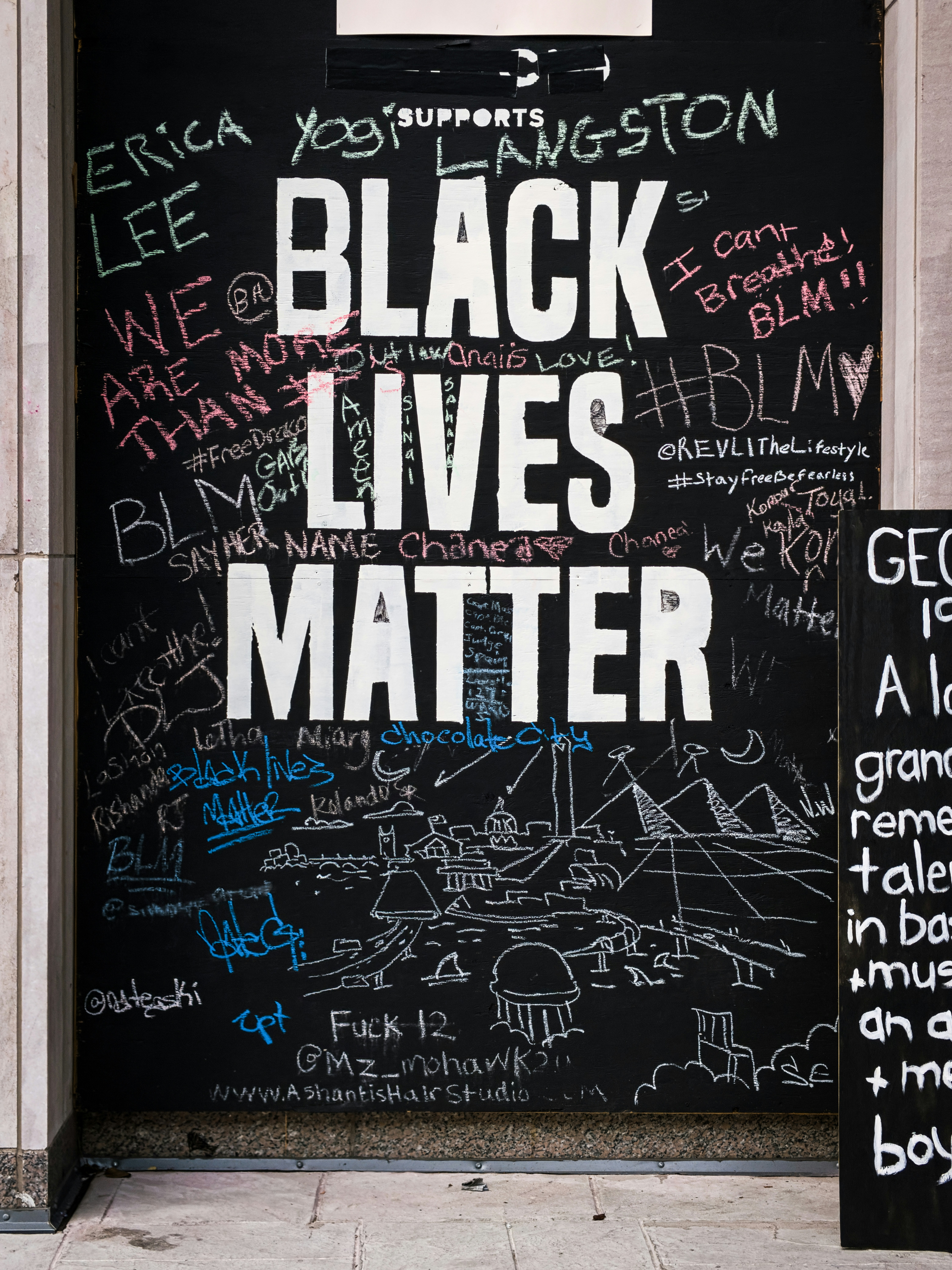 A vibrant mural advocating for Black Lives Matter, adorned with various messages and signatures reflecting community support and activism.