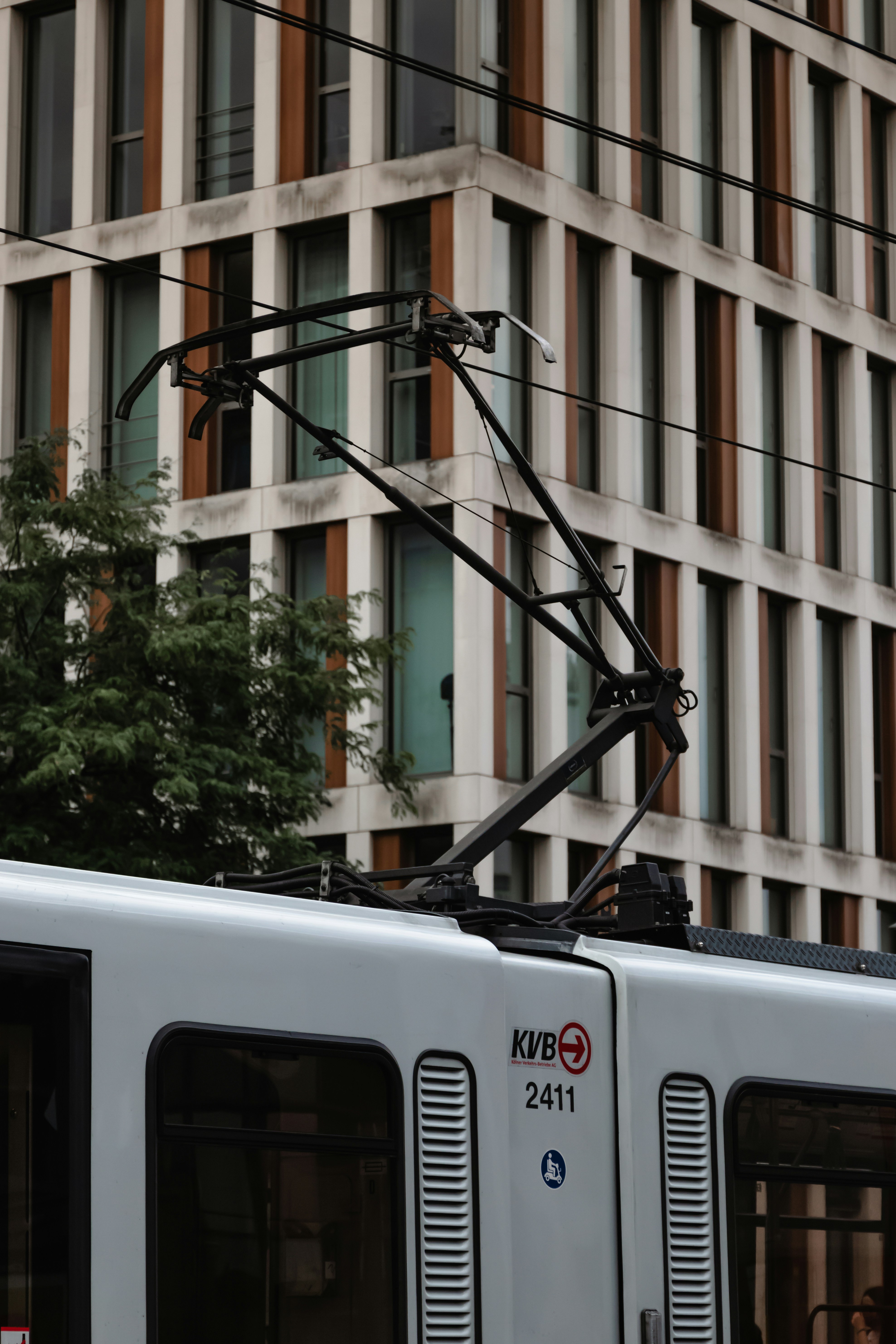 Electric tram's overhead line against a backdrop of contemporary building design with striking geometric patterns.