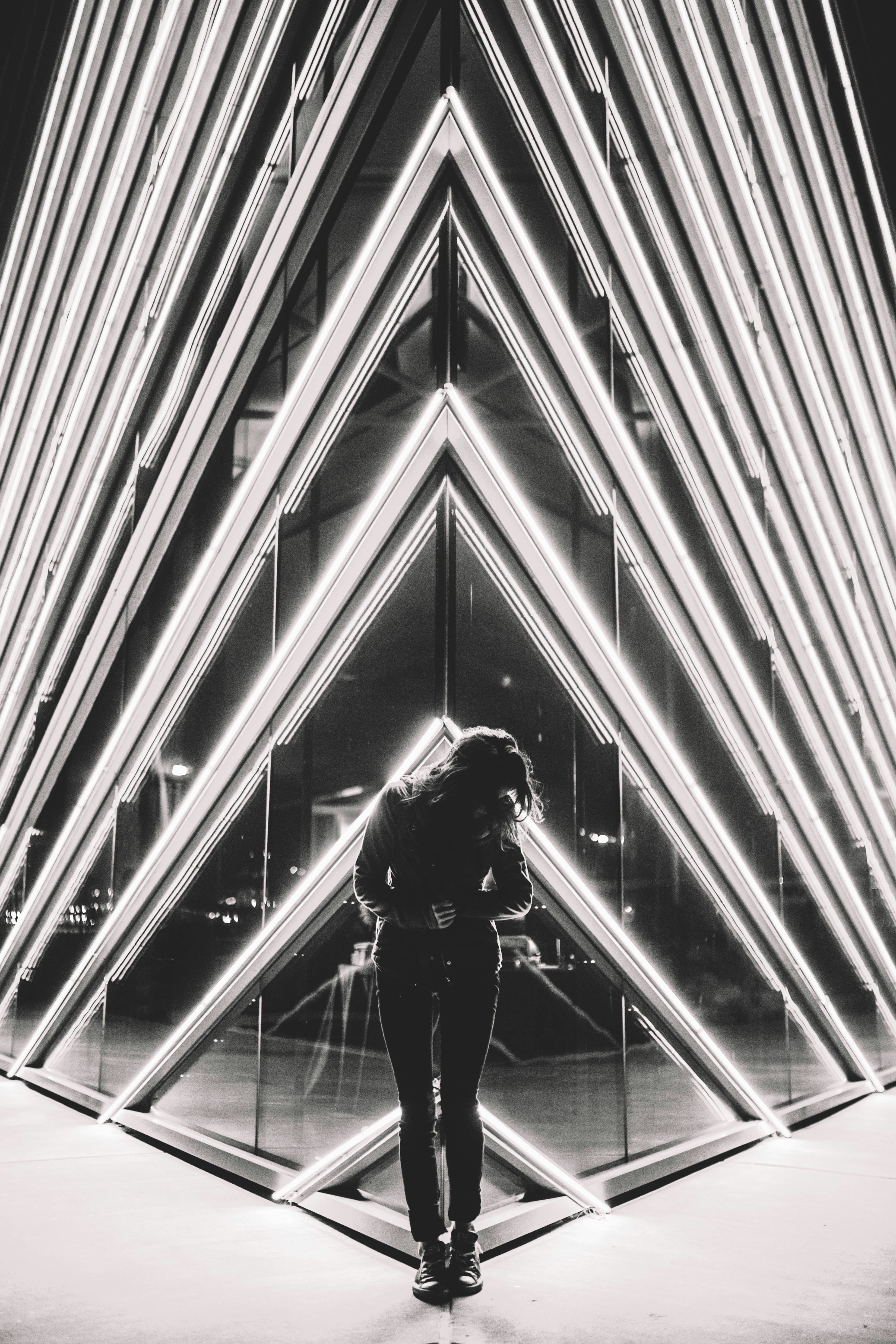 Neon Triangle Cathedral: A lone silhouette amid mirrored neon arches