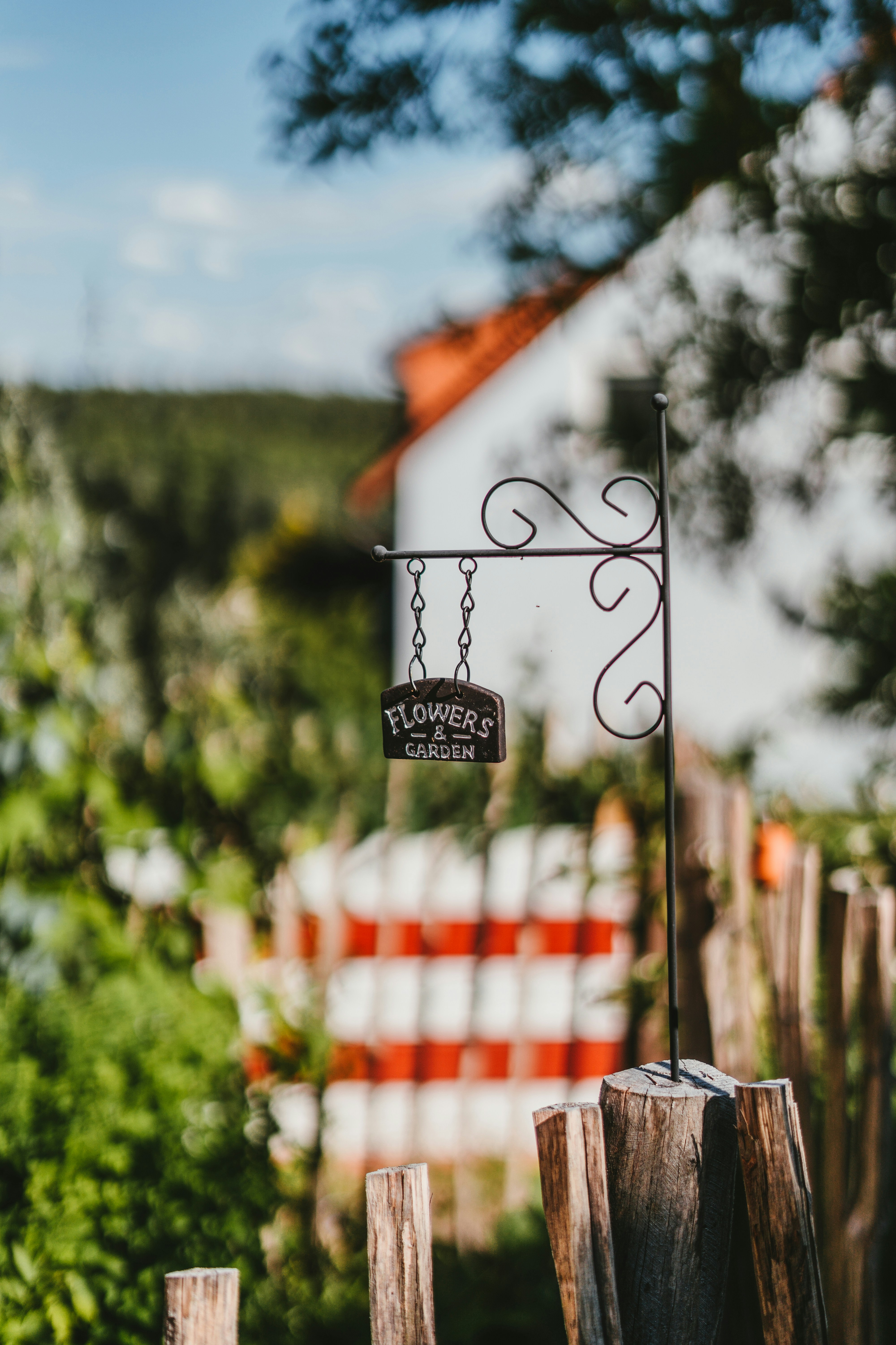 Iron Whimsy: A Hanging Flower Sign Between Weathered Posts