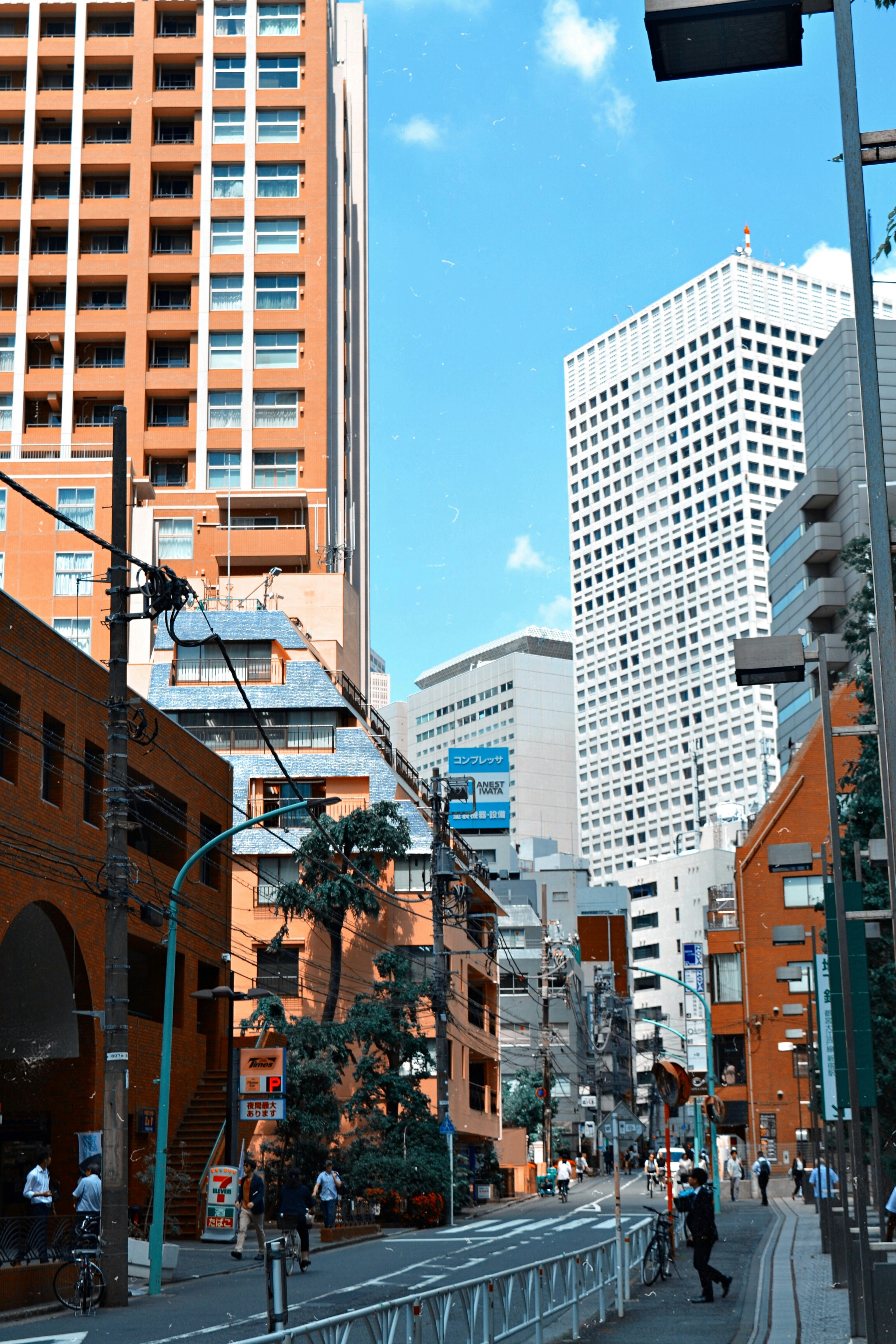 Dynamic city street scene showcasing a blend of modern and traditional architecture, bustling with pedestrians and vibrant greenery.