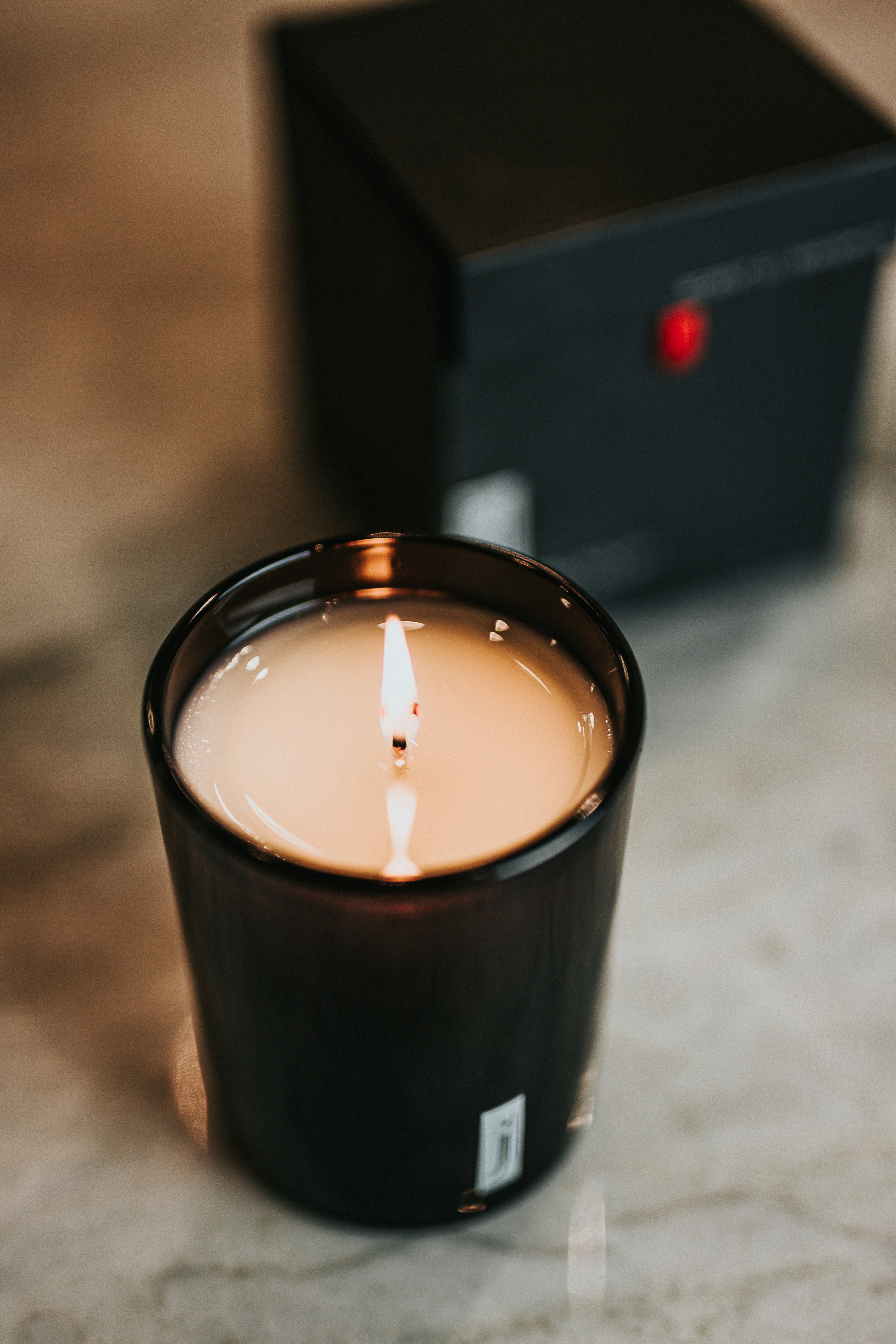 Lone Candle in a Matte Jar Casts a Warm Glow Across Marble