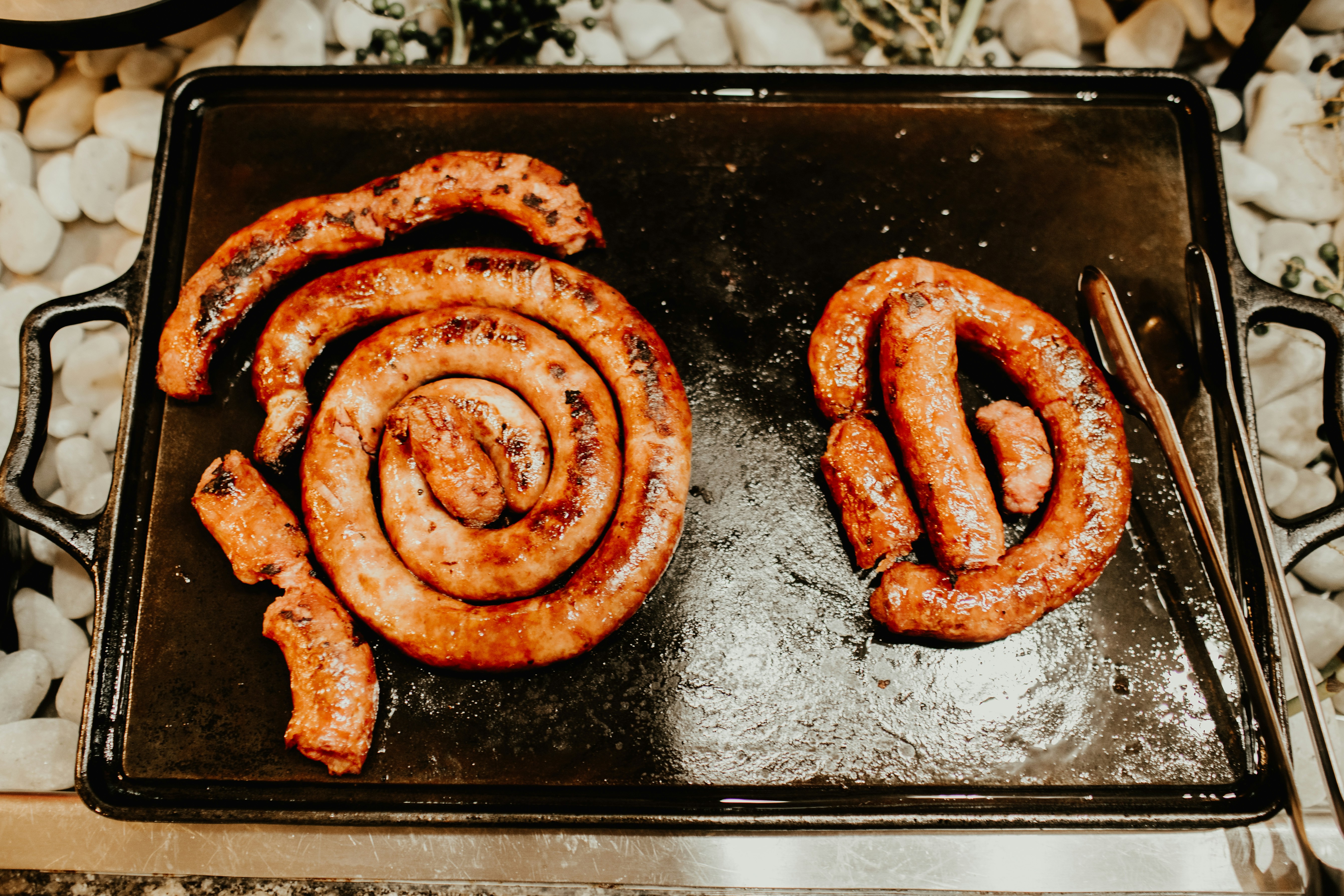 Spiral Sausage Griddle: Two Charred Spirals on a Black Tray