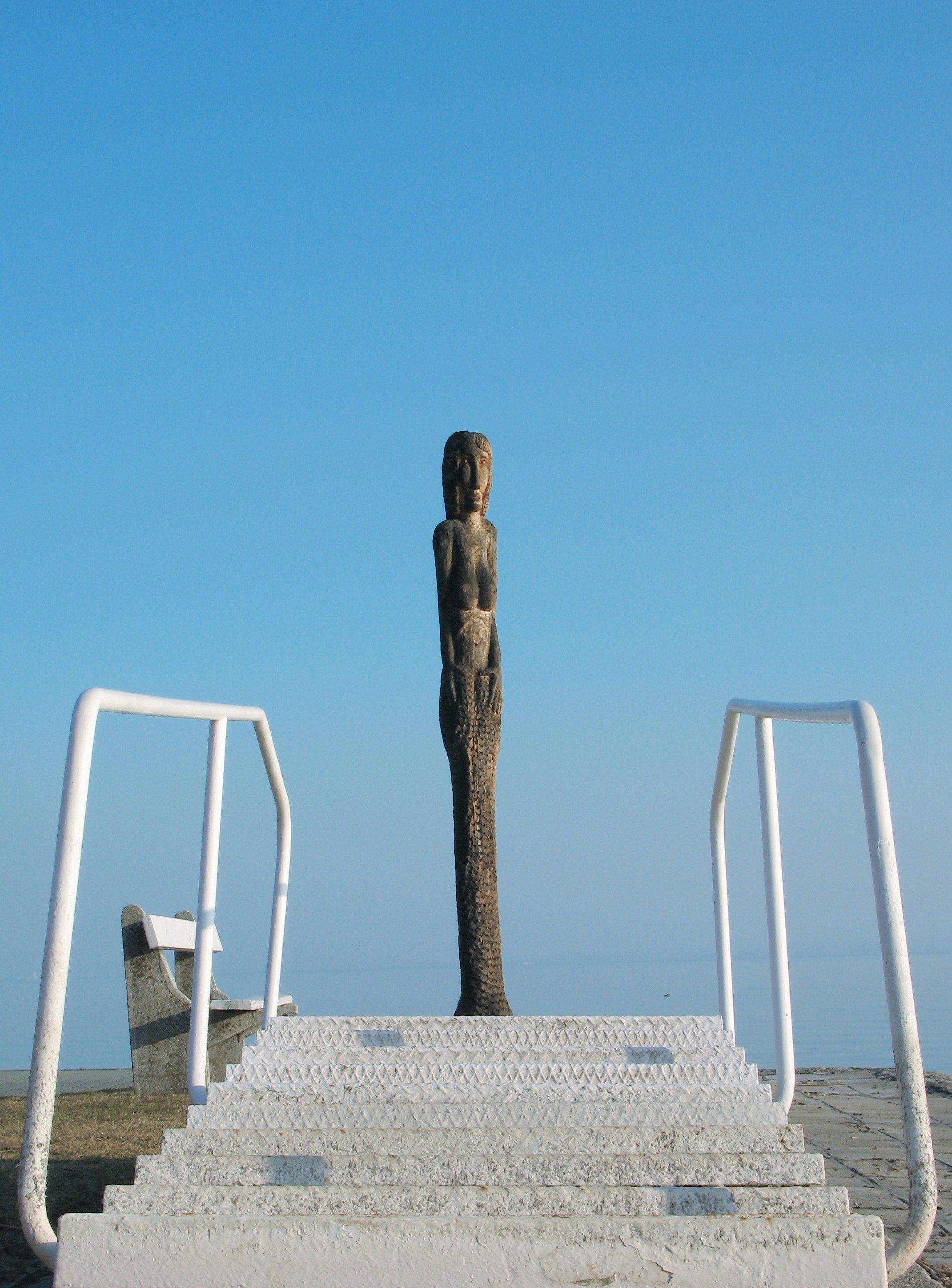 Stone Sentinel on White Staircase Reaches Toward a Cerulean Sky