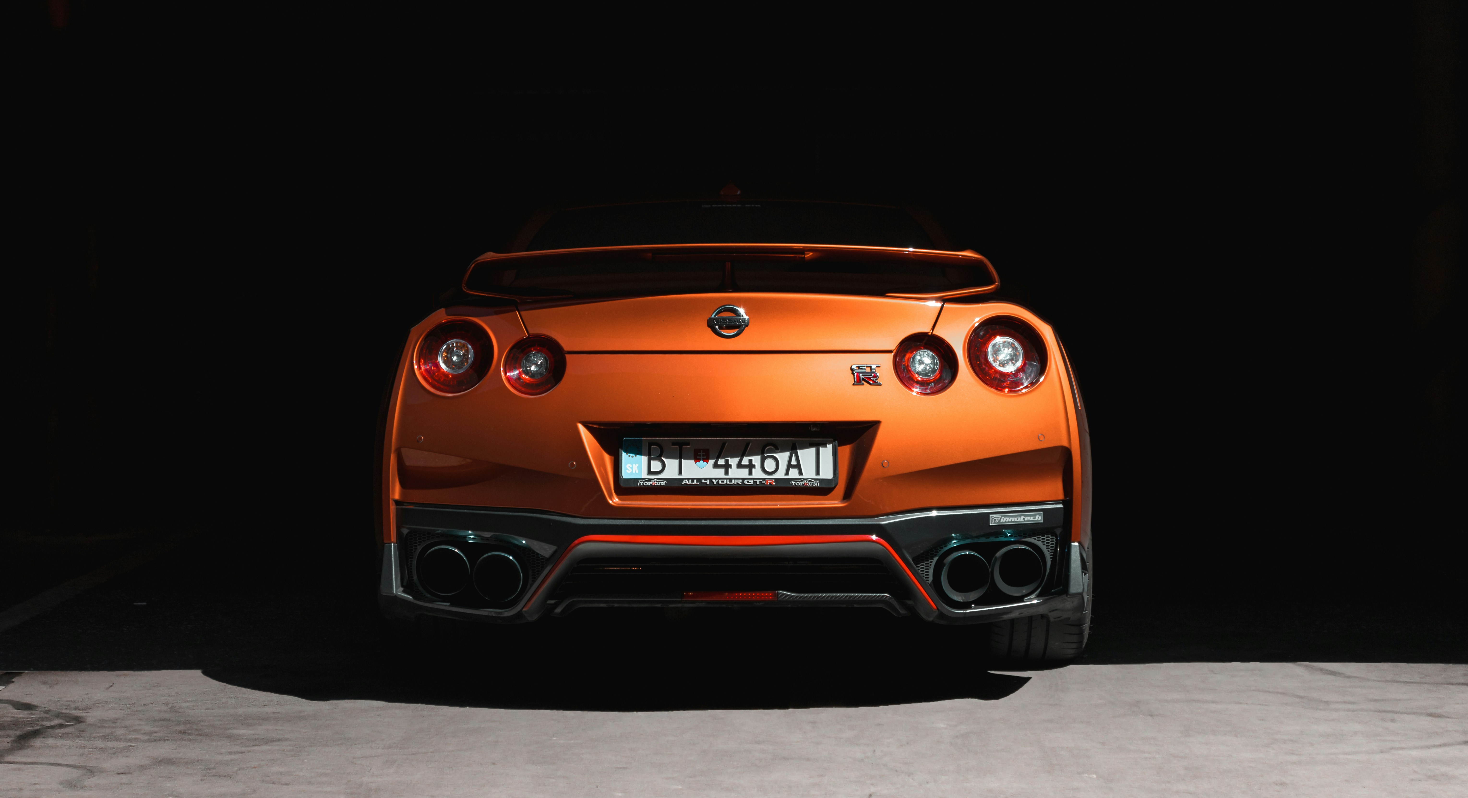 Vivid orange sports car positioned against a dark backdrop, highlighting its sleek design and bold curves.