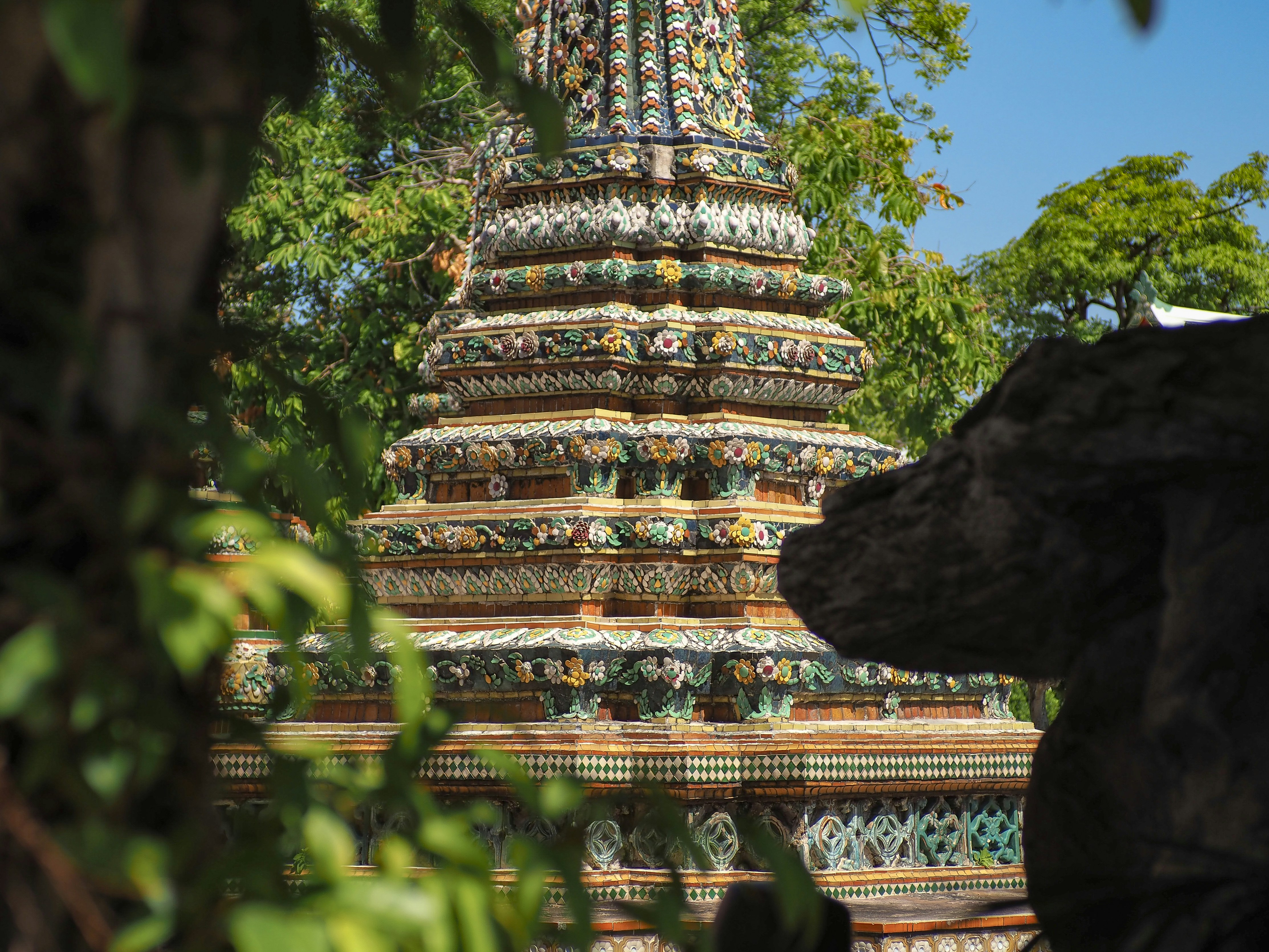 Emerald-framed Stupa: A jewel-toned tiered monument peeking through lush foliage