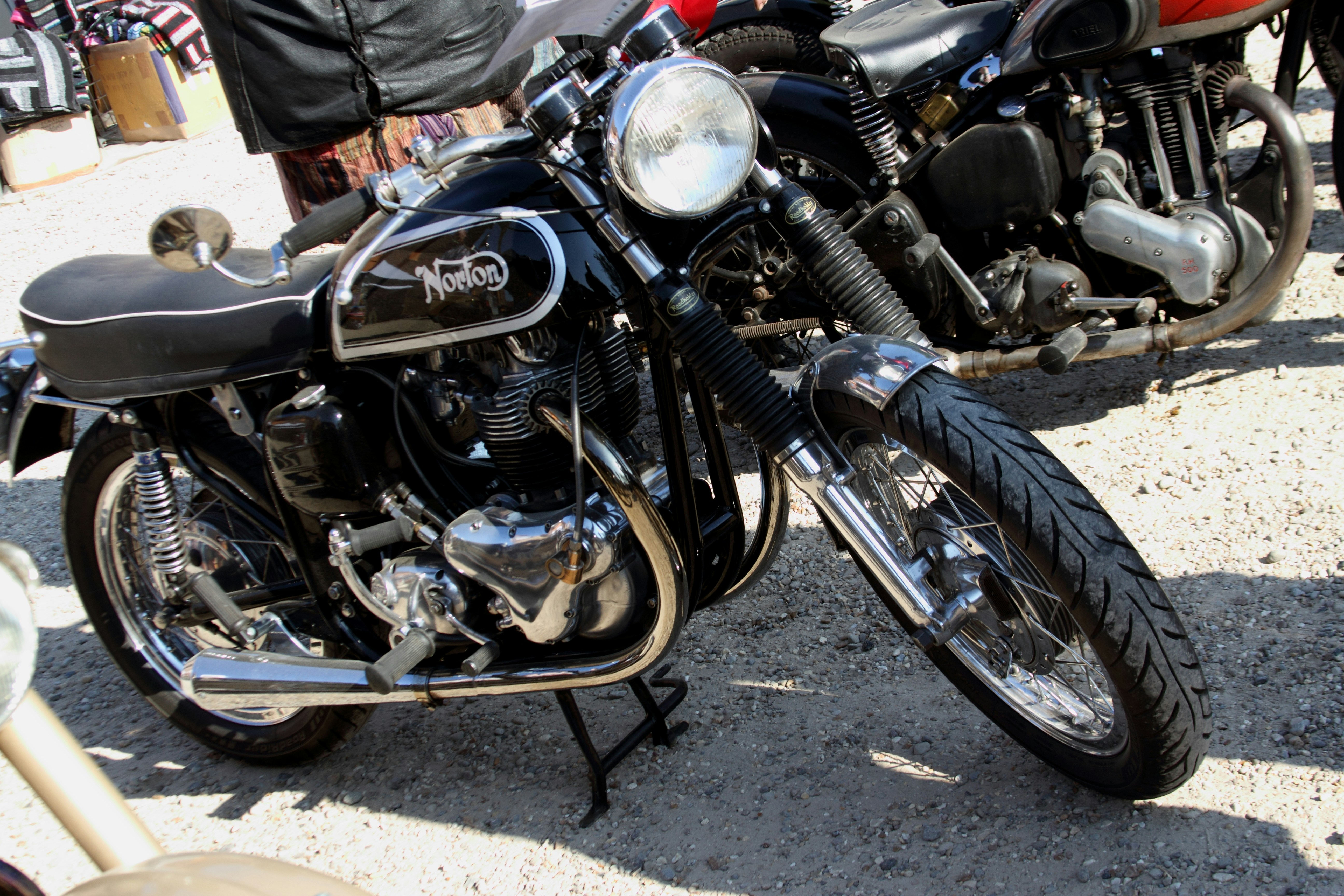 Classic black Norton motorcycle parked on a sunny day.