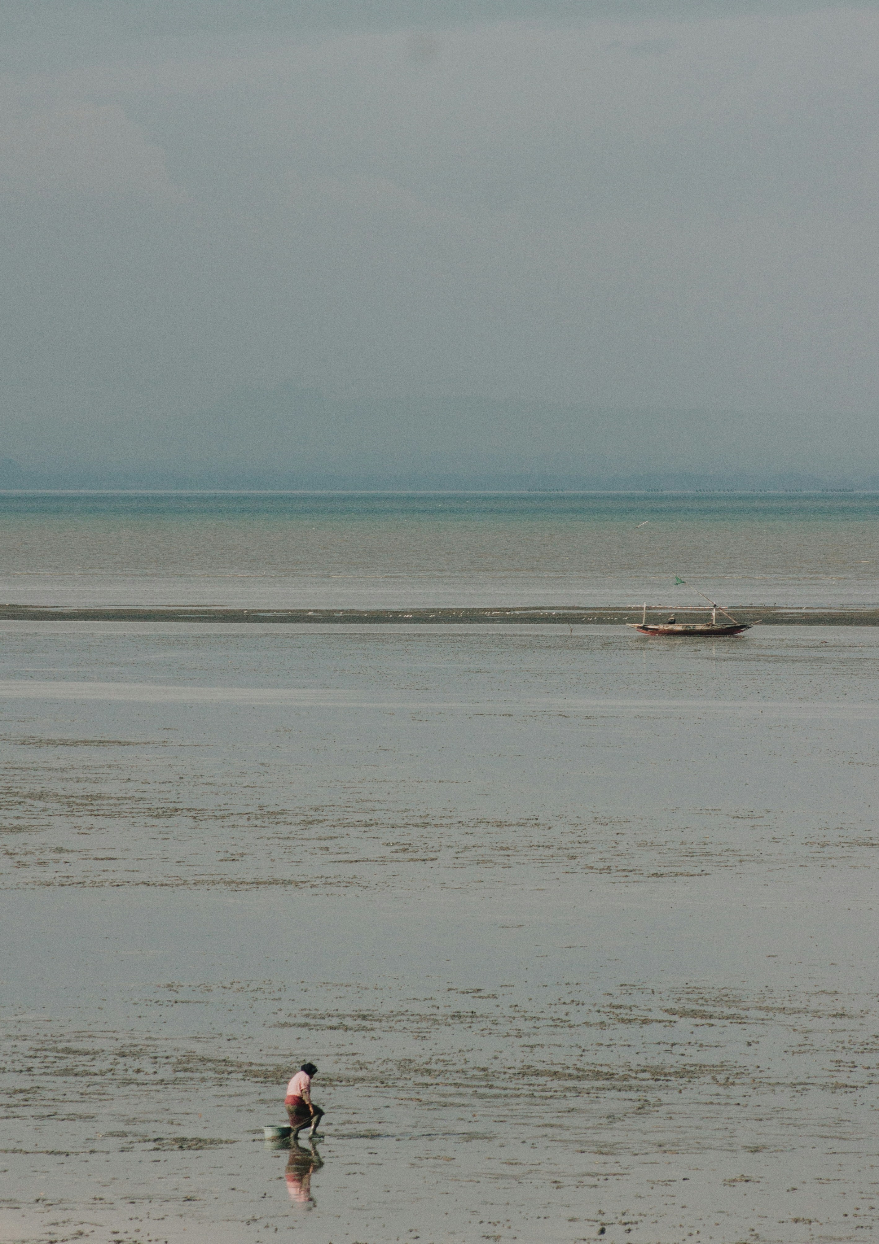 Low Tide Walk: A Lone Figure and a Distant Boat on a Quiet Shore