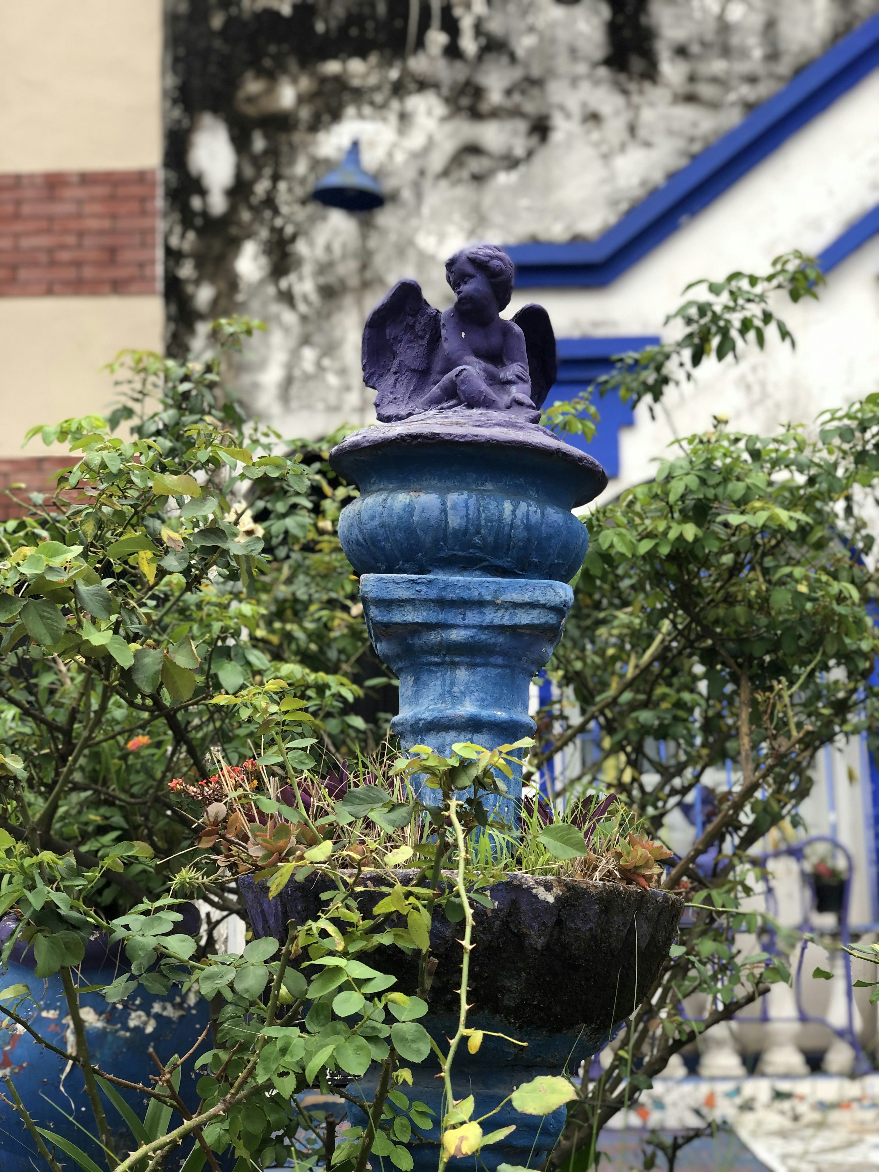 blue concrete statue near green plants during daytime