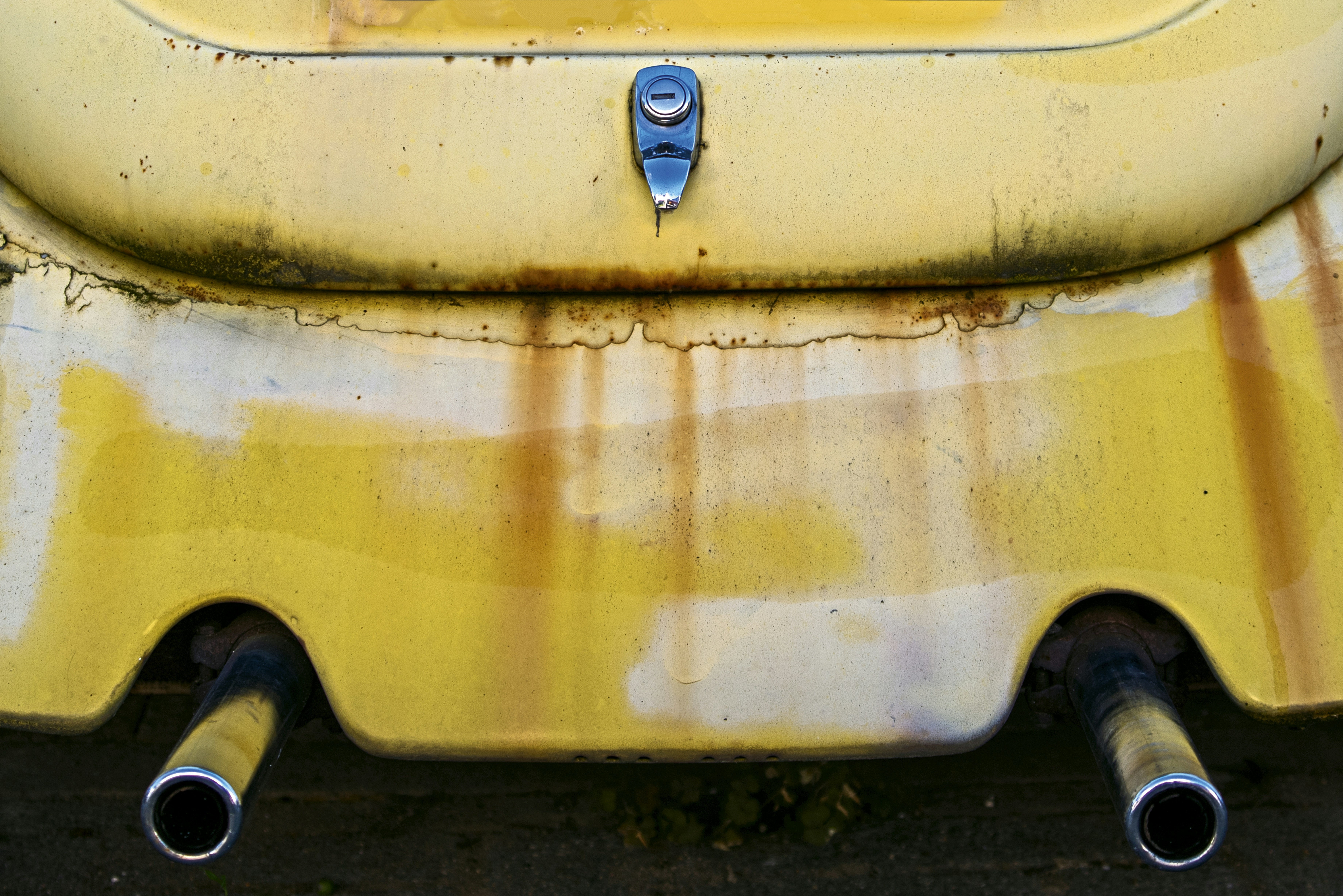 Centered Latch Amid Rusted Yellow Patina on a Vintage Car