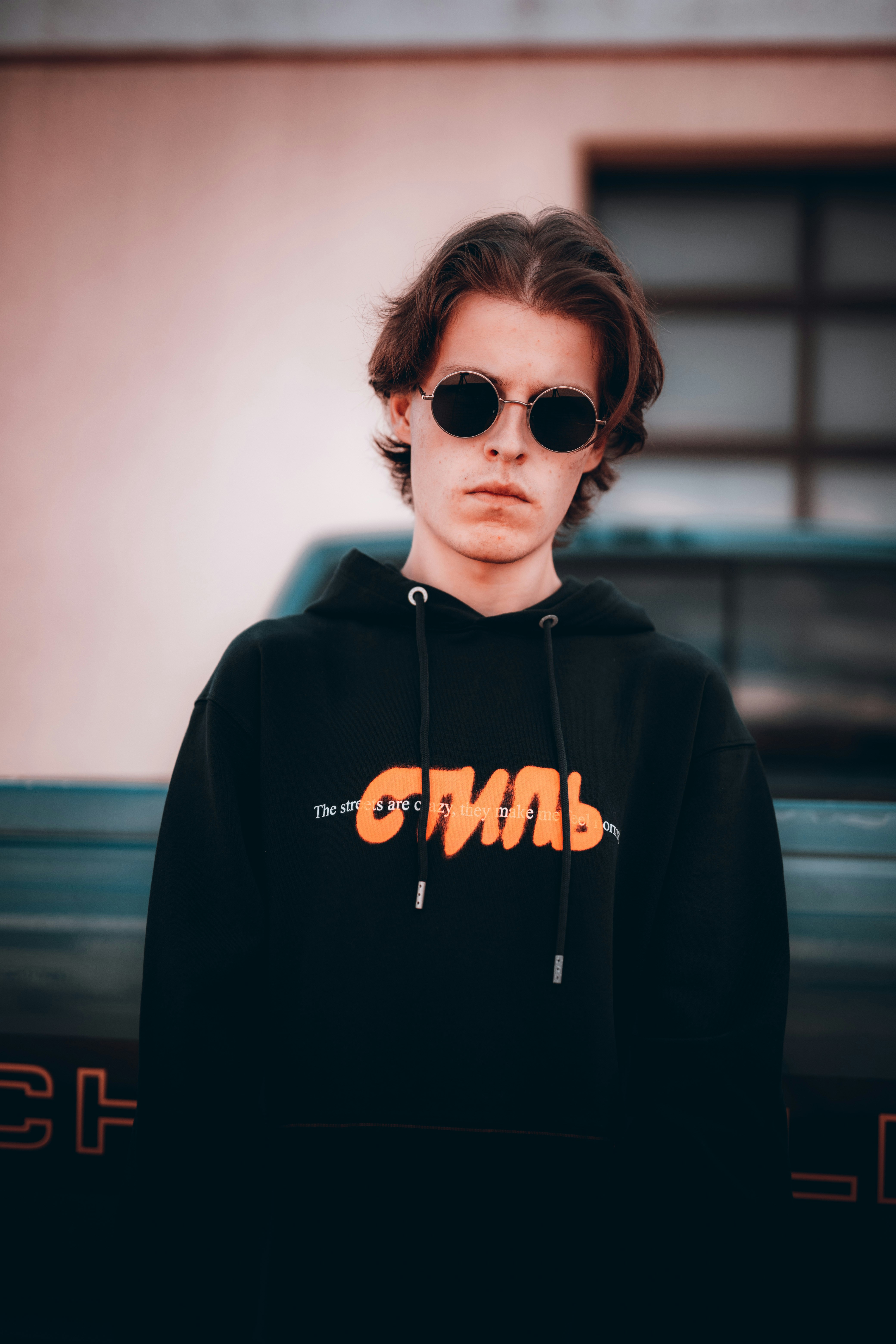 Quiet Edge: Portrait in Round Sunglasses and an Orange-Graphic Hoodie