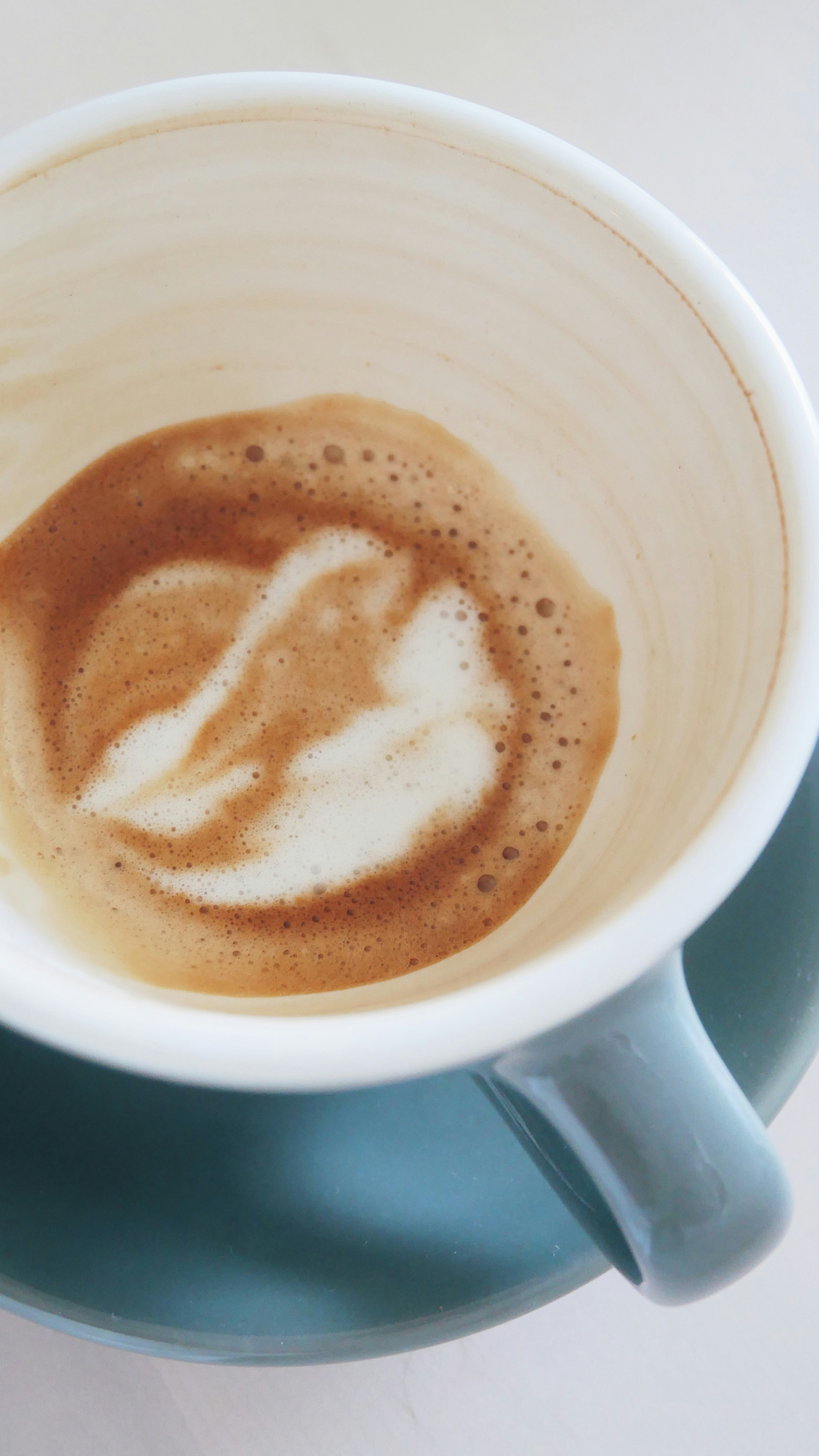 A close-up view of a coffee cup showcasing intricate latte art resembling a swan, set against a soft background. The smooth texture and warm tones create a cozy atmosphere.