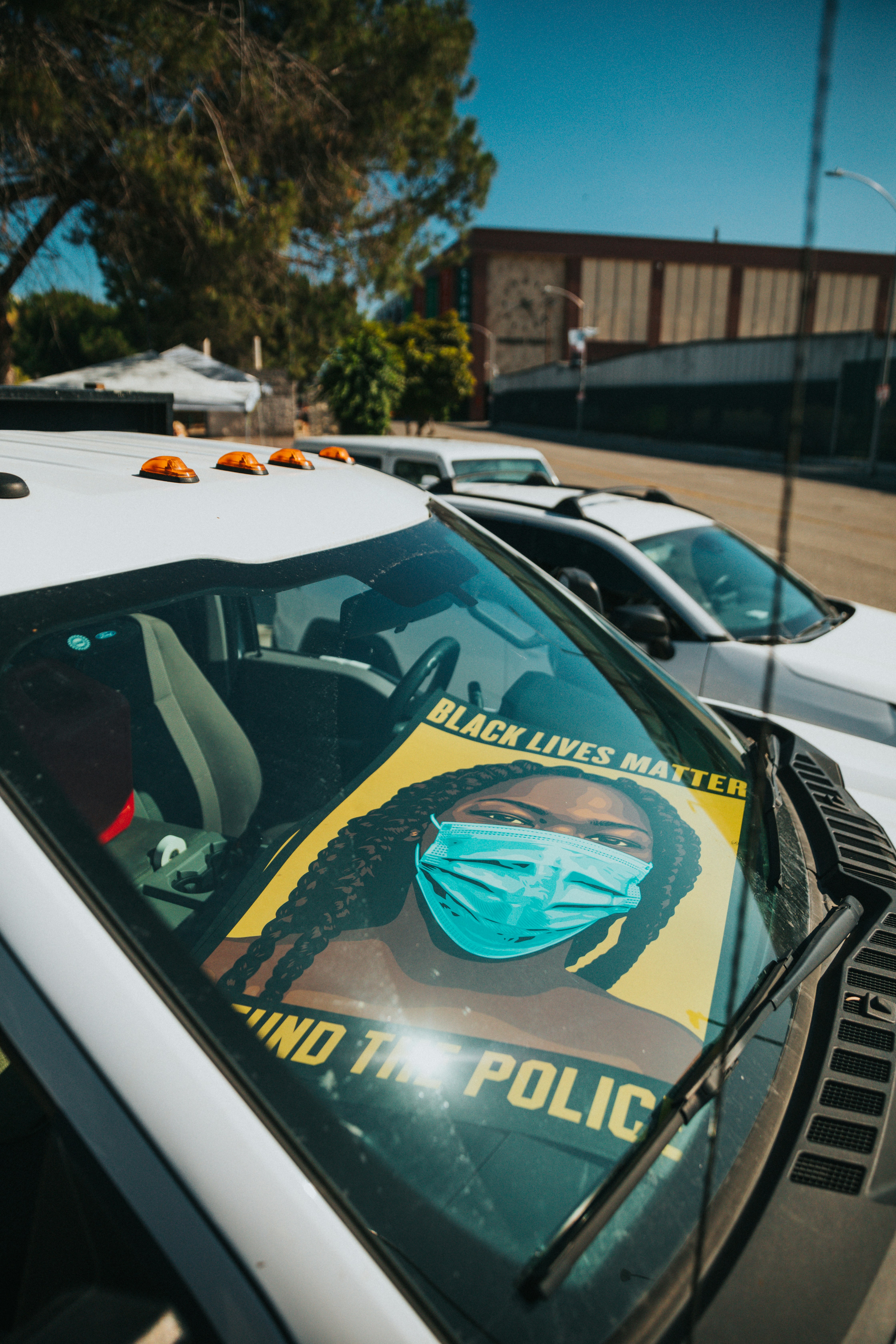 Masked Message on the Windshield: A Protest Poster Framed in a Parked Vehicle