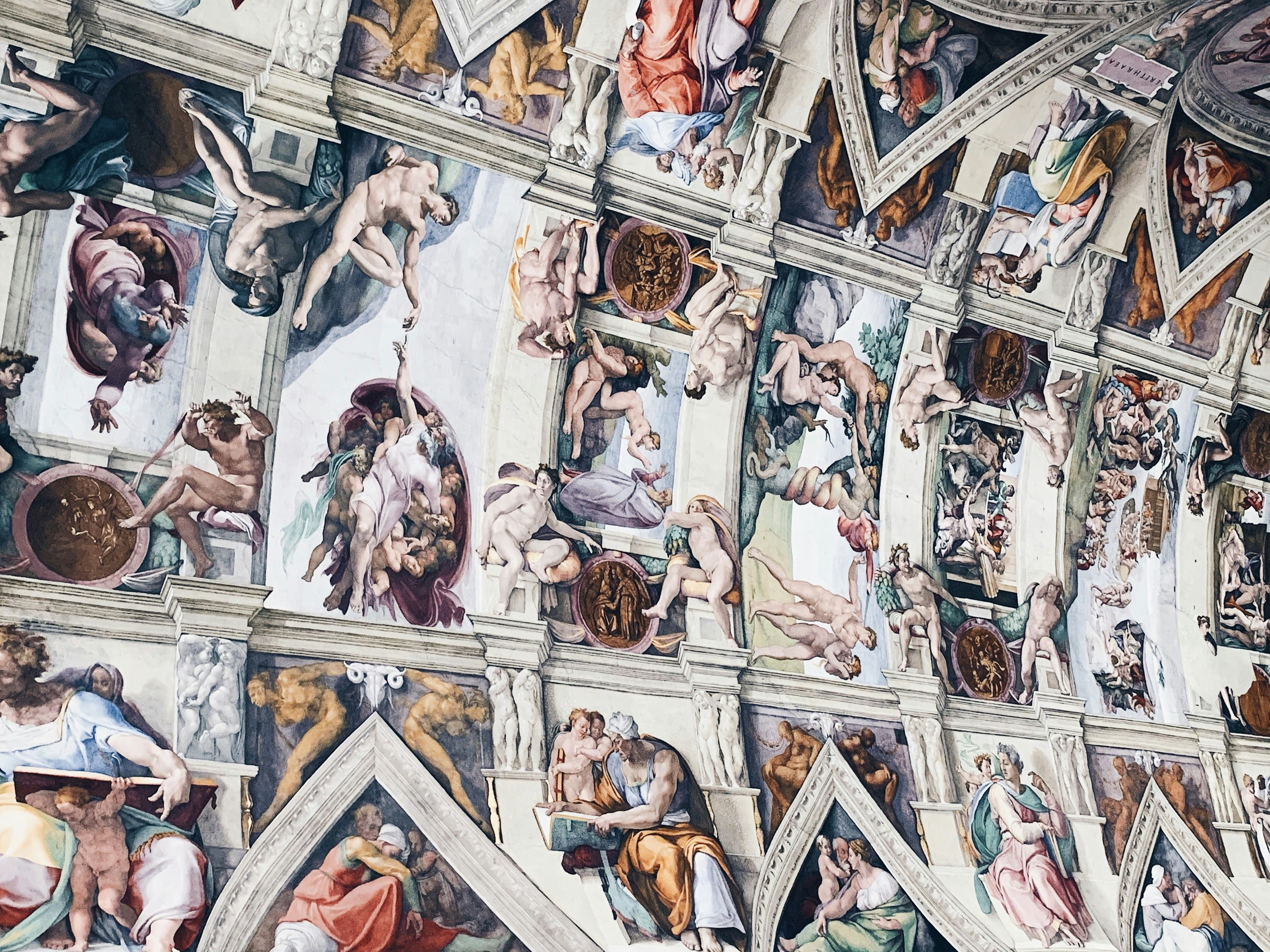 Intricate frescoes adorning the ceiling of the Sistine Chapel, showcasing biblical scenes and figures in dynamic poses.