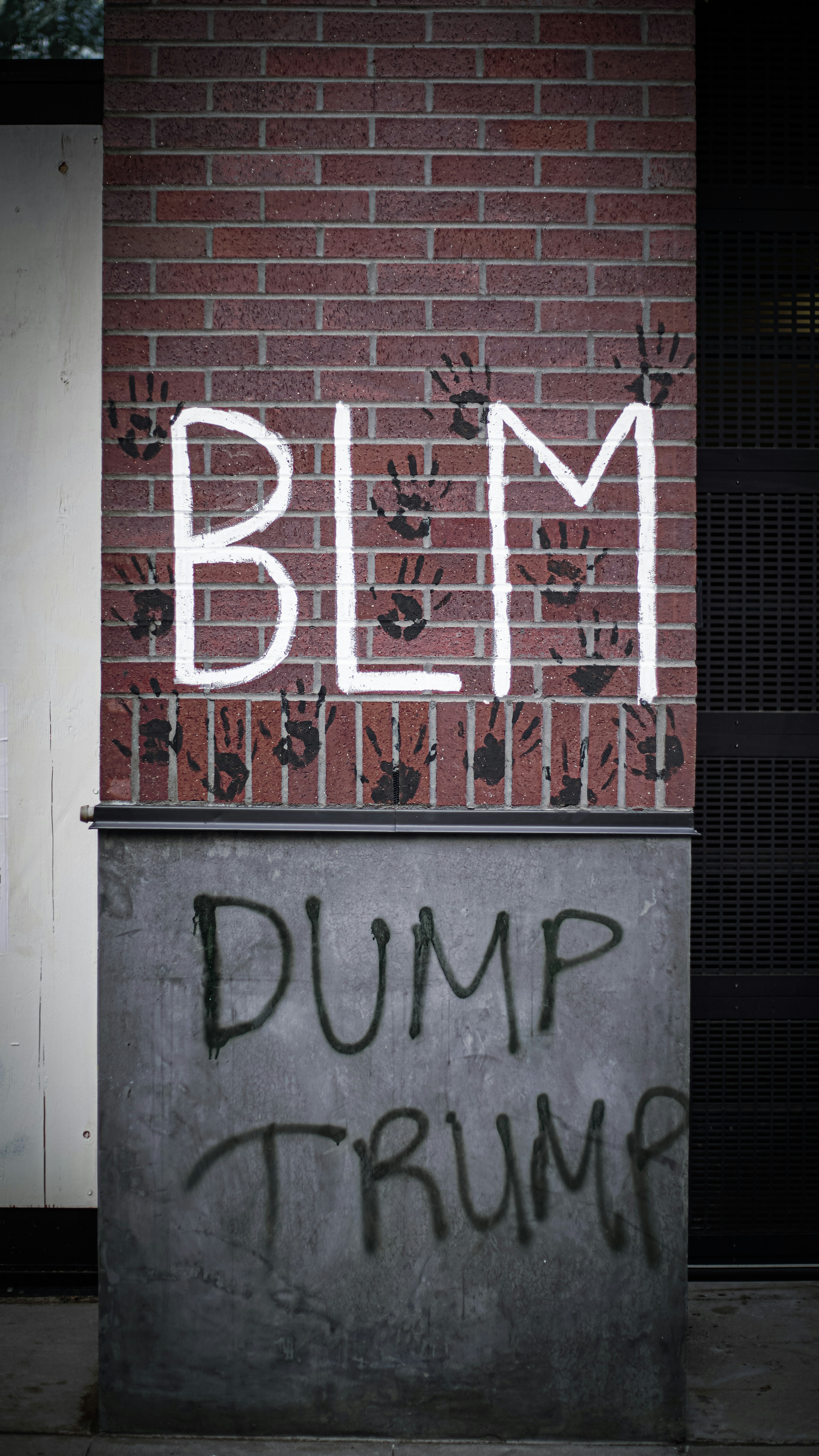 Bleached Brick Protest: BE M and DUMP TRUMP graffitied on urban facade
