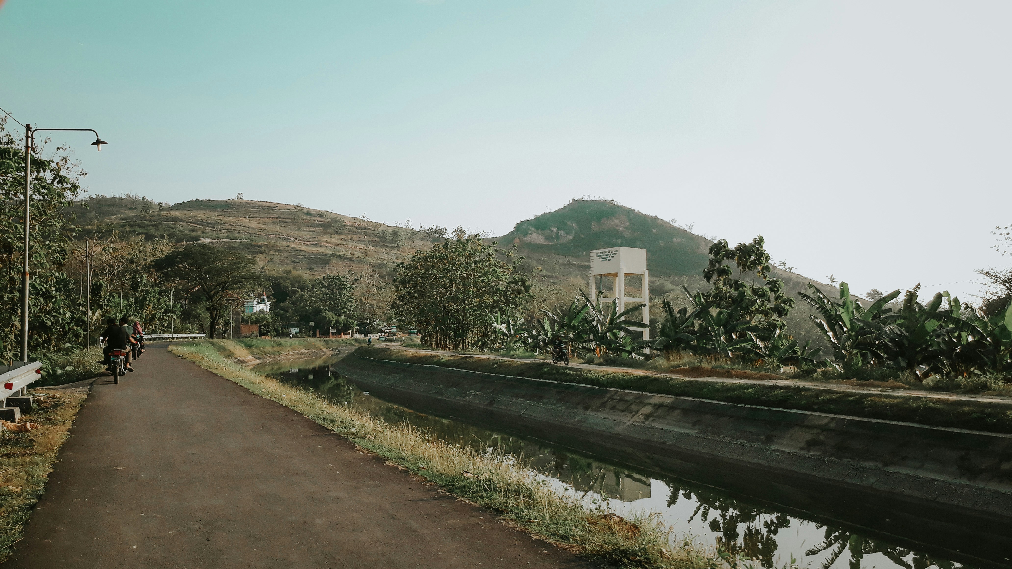 Pathway alongside a canal with distant hills under a clear sky.