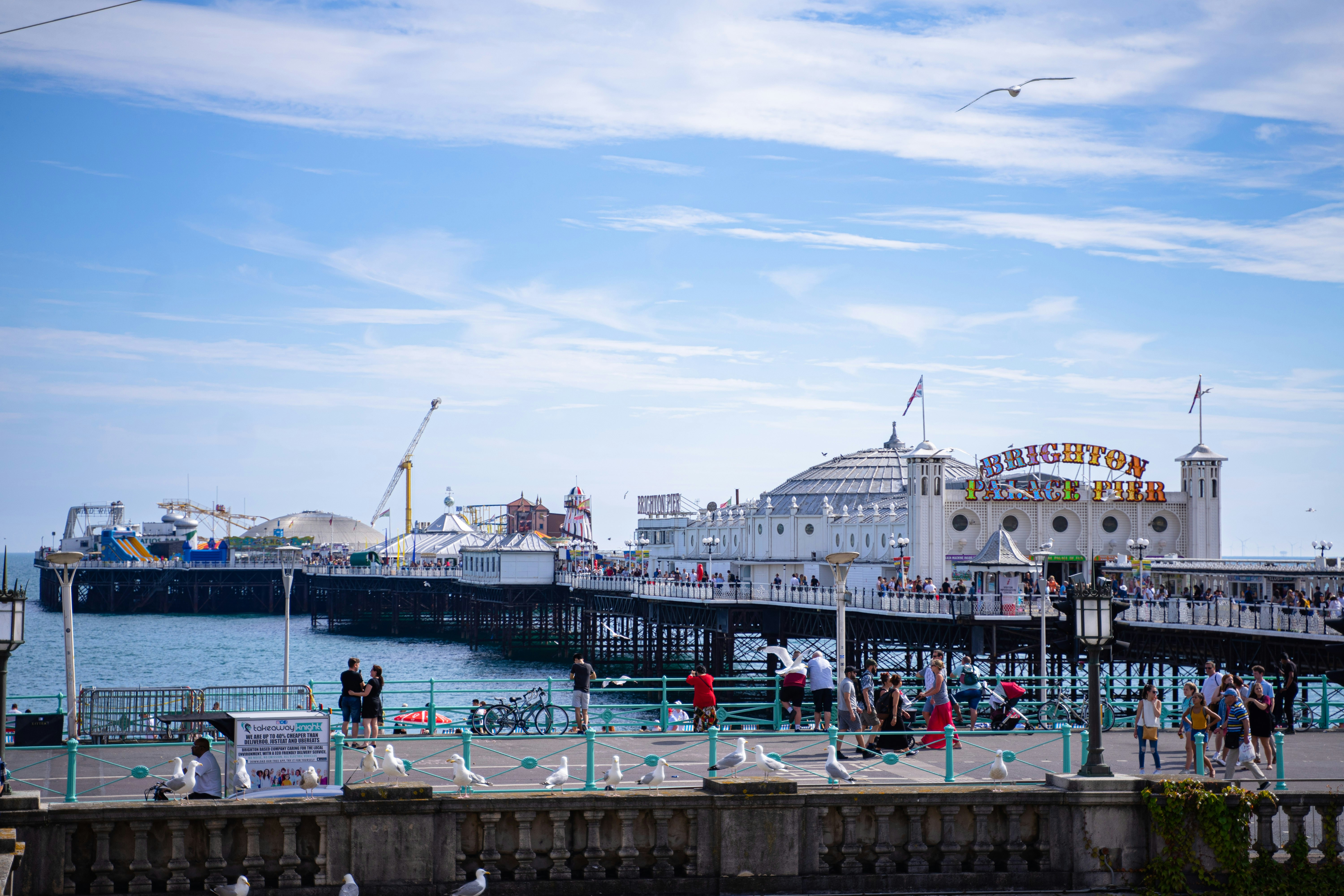 Brighton Pier at Noon: A Bustling Seaside Scene Under a Cloud-Streaked Sky