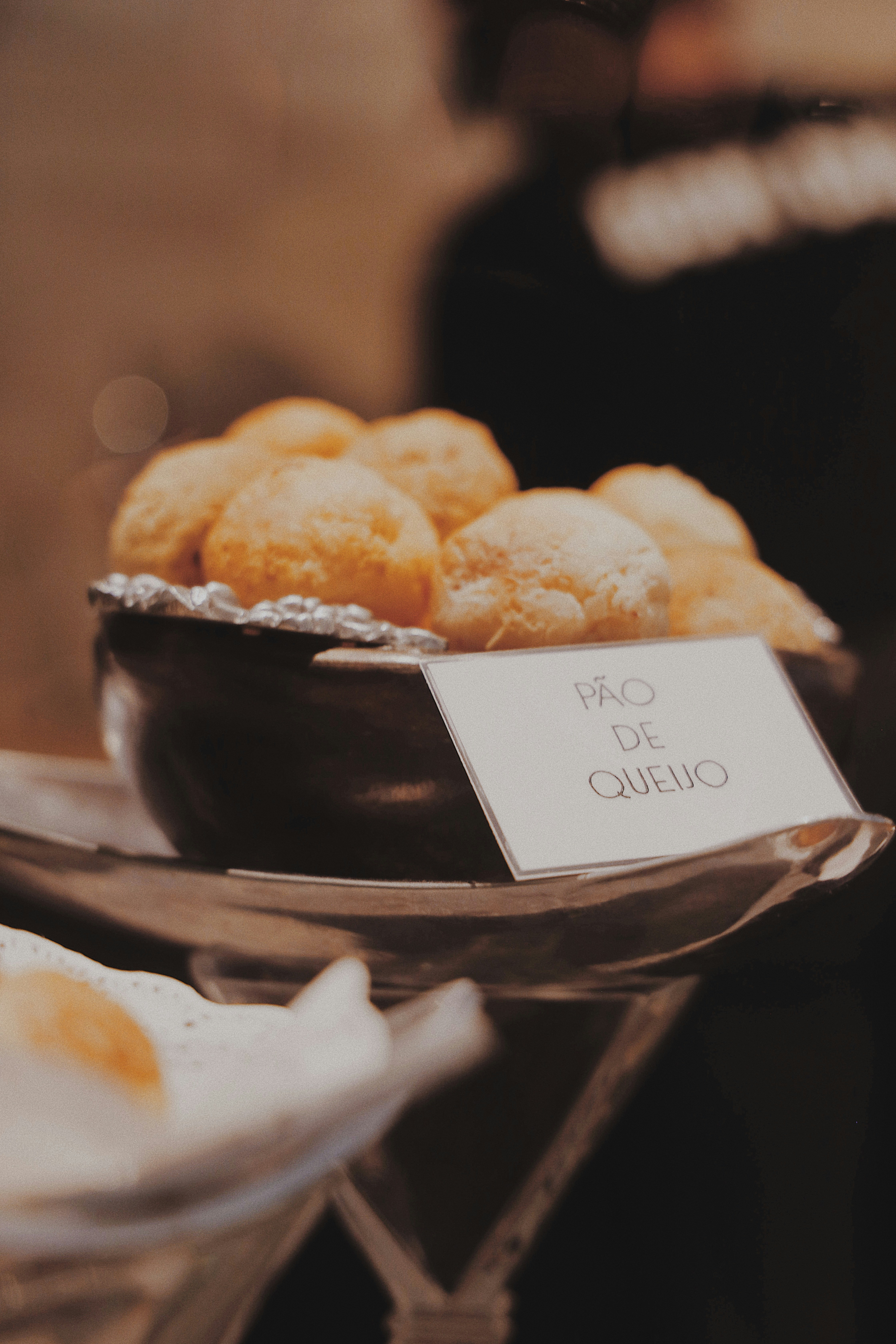 Golden Puffs Under Café Glow: Pão de Queijo on a Shimmering Tray