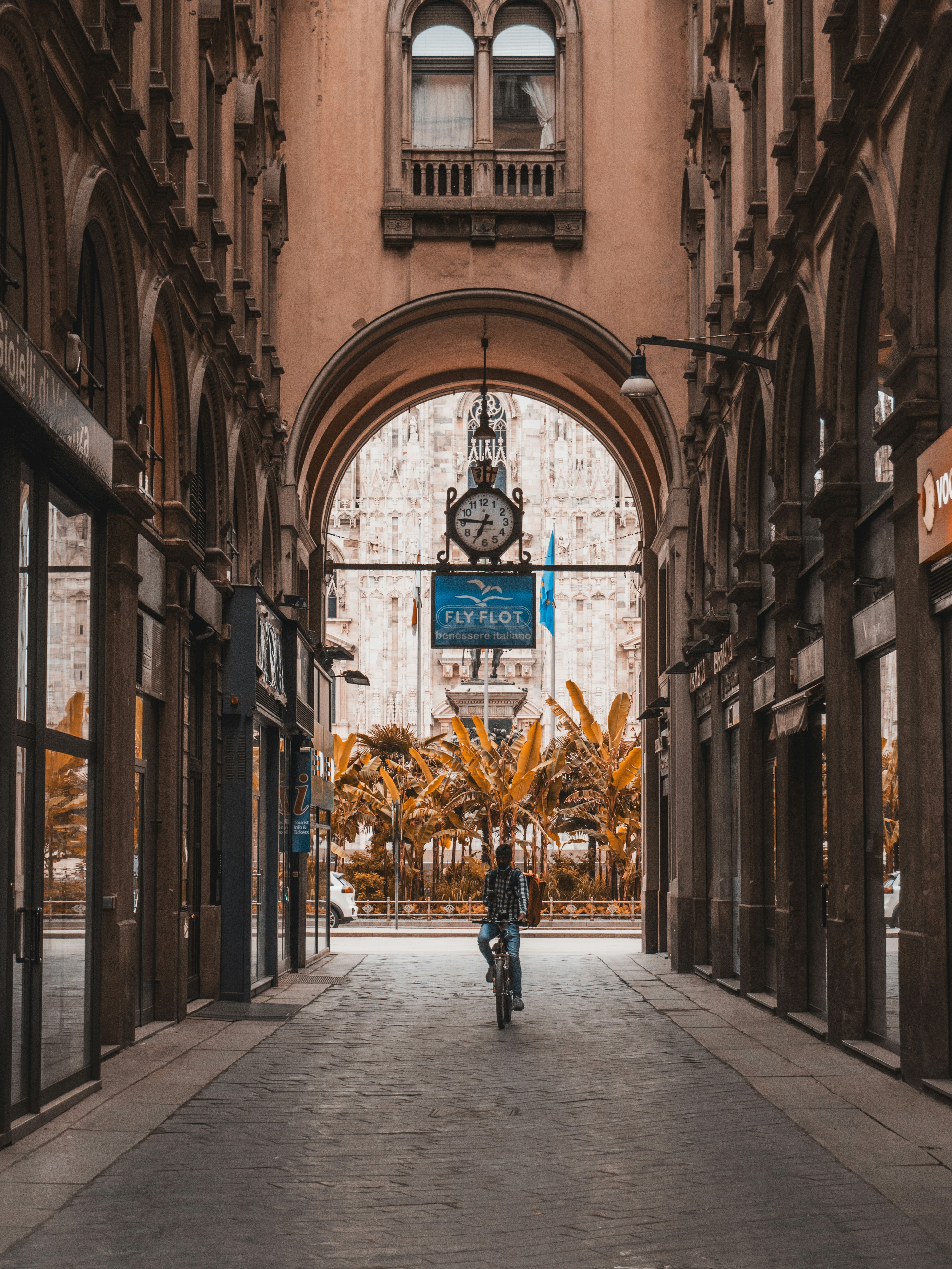 Arcade to the Clock: Cyclist under the Archway toward the Sunny Plaza
