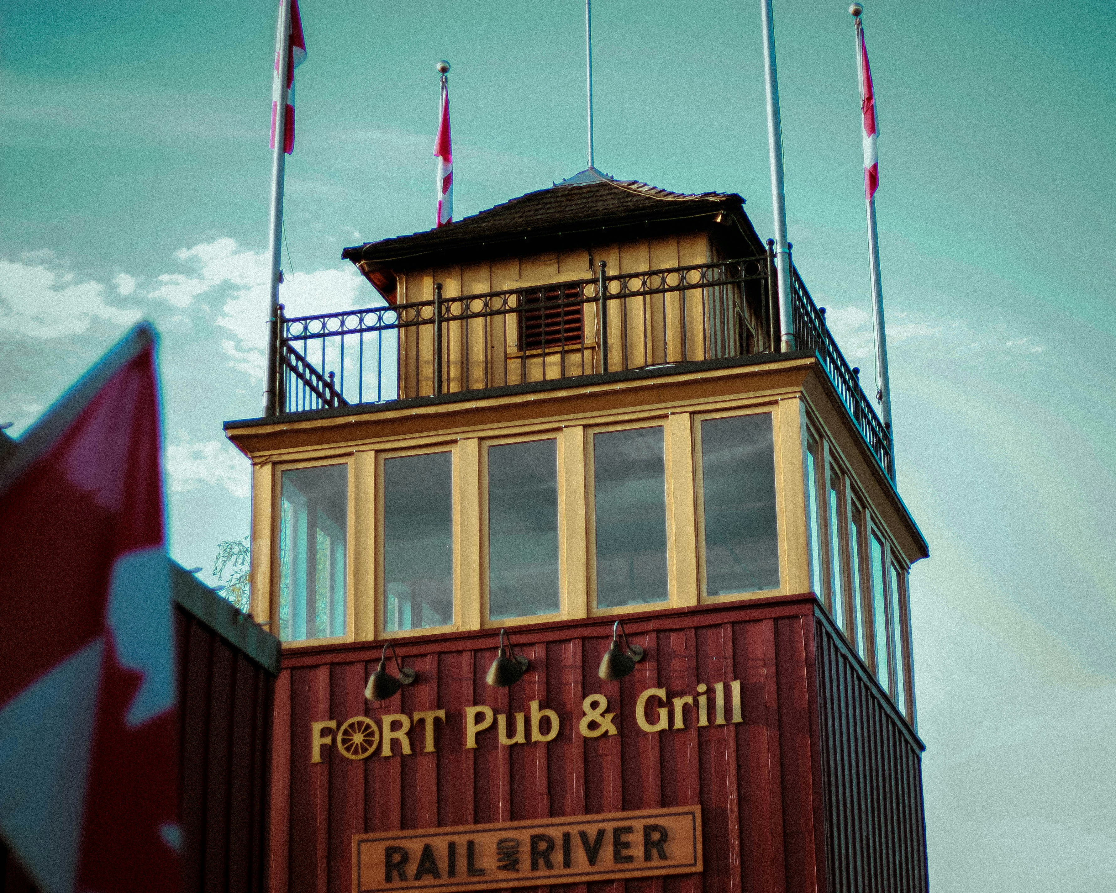 Fort Pub & Grill Tower: A Weathered Naval Lookout Over Rails and Flags