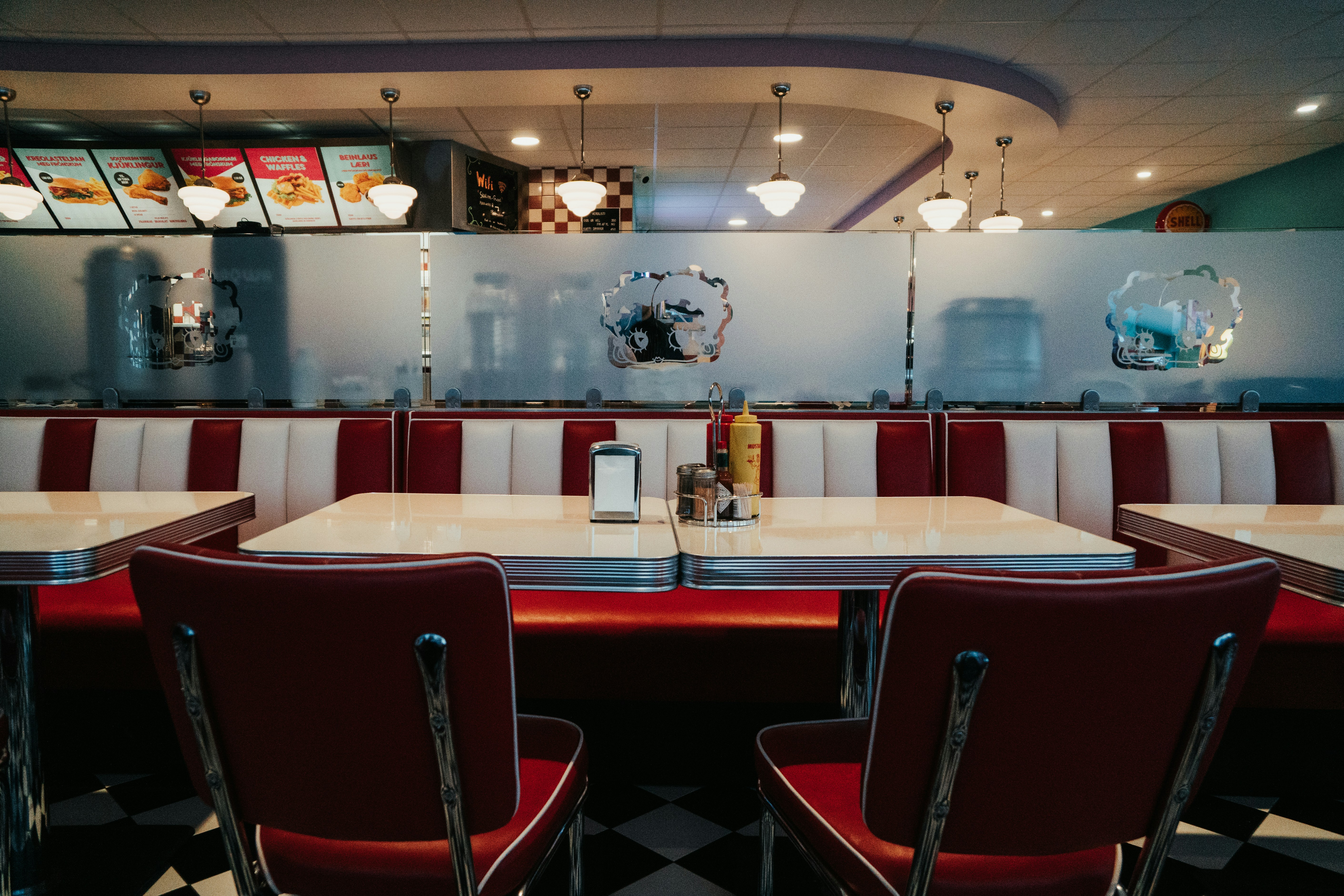 Classic diner interior with red and white booths and vintage decor under soft lighting.