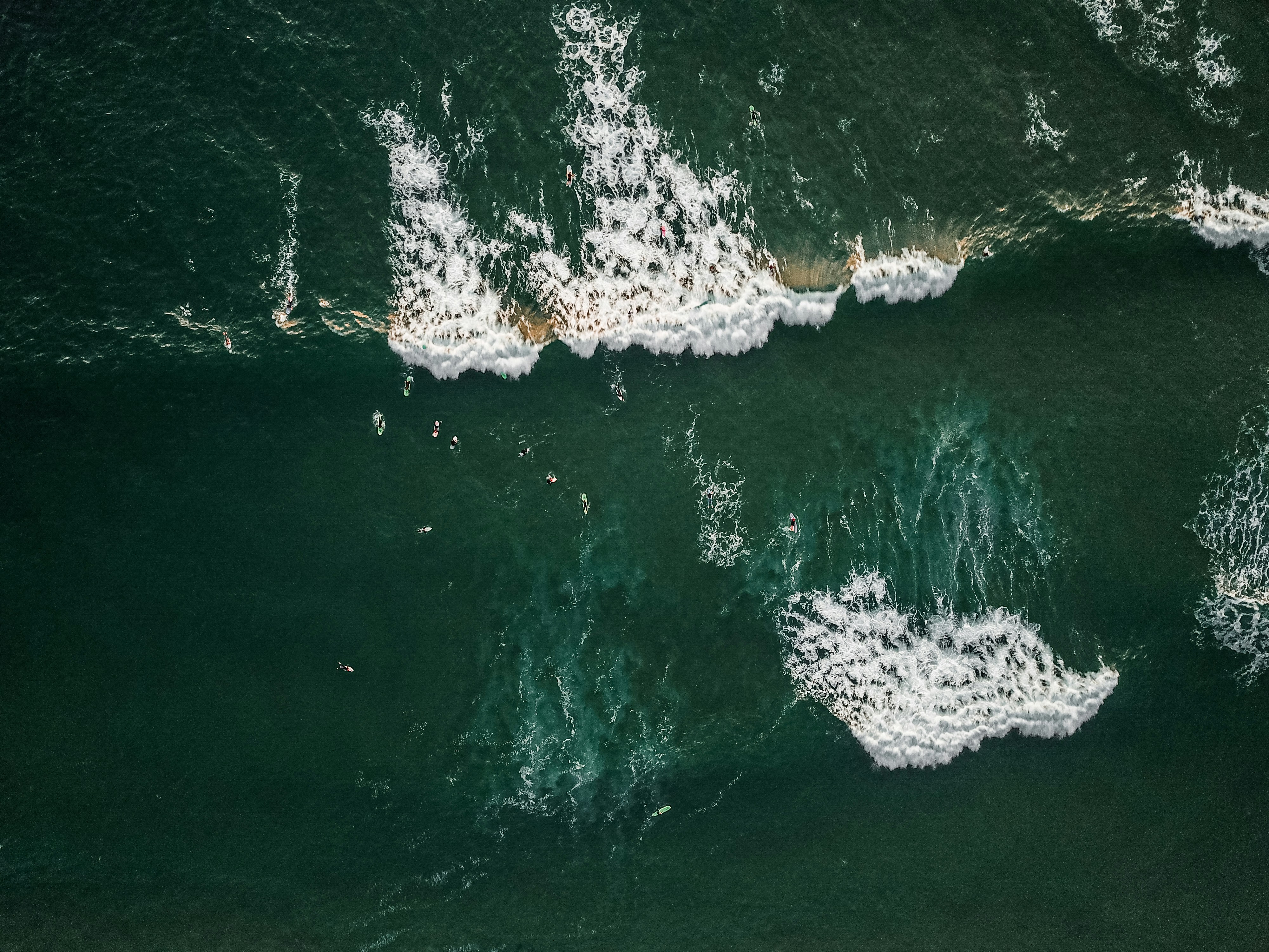 Aerial perspective of dark green sea waves crashing and frothing against each other.