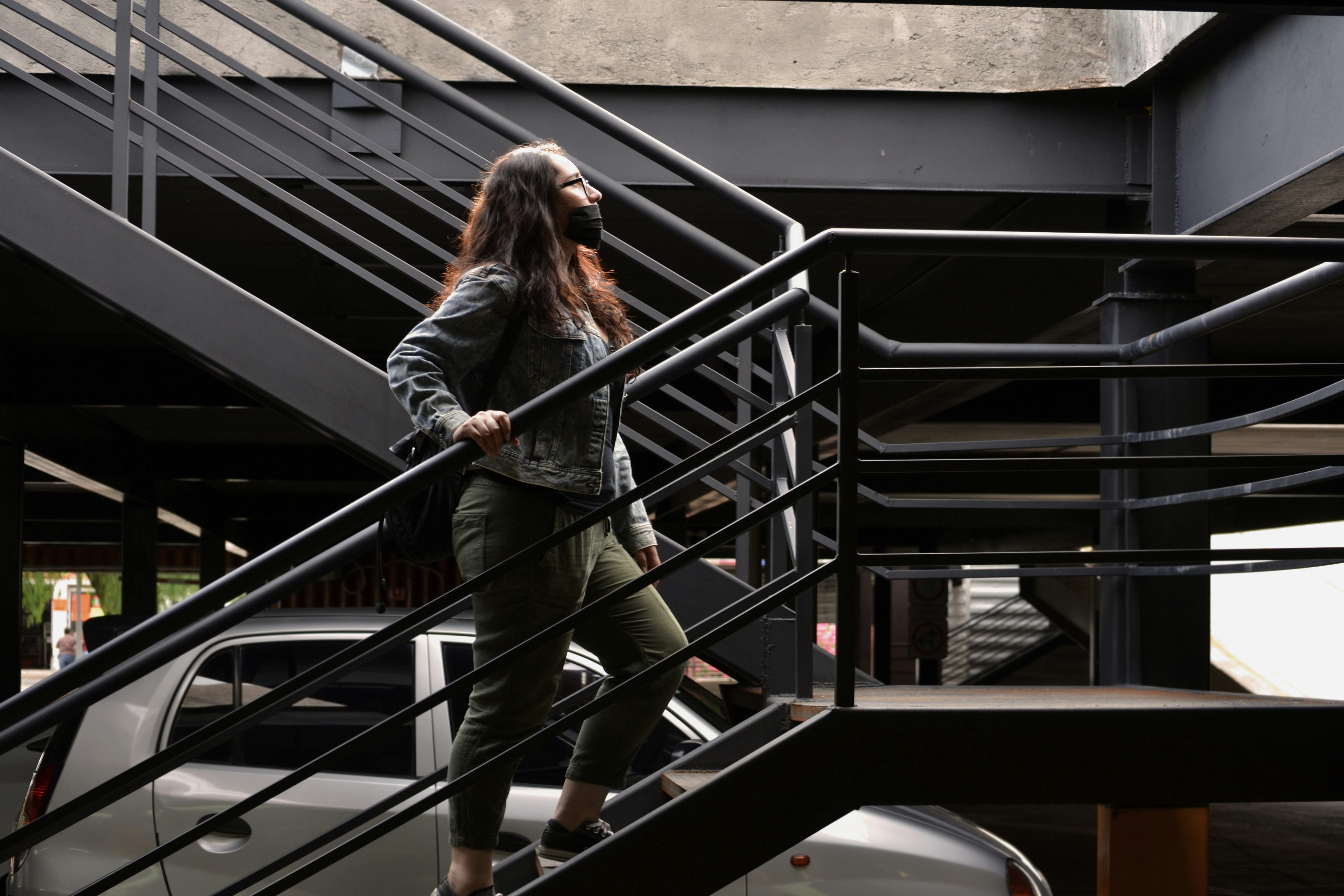 woman in blue denim jacket and black pants standing on black staircase