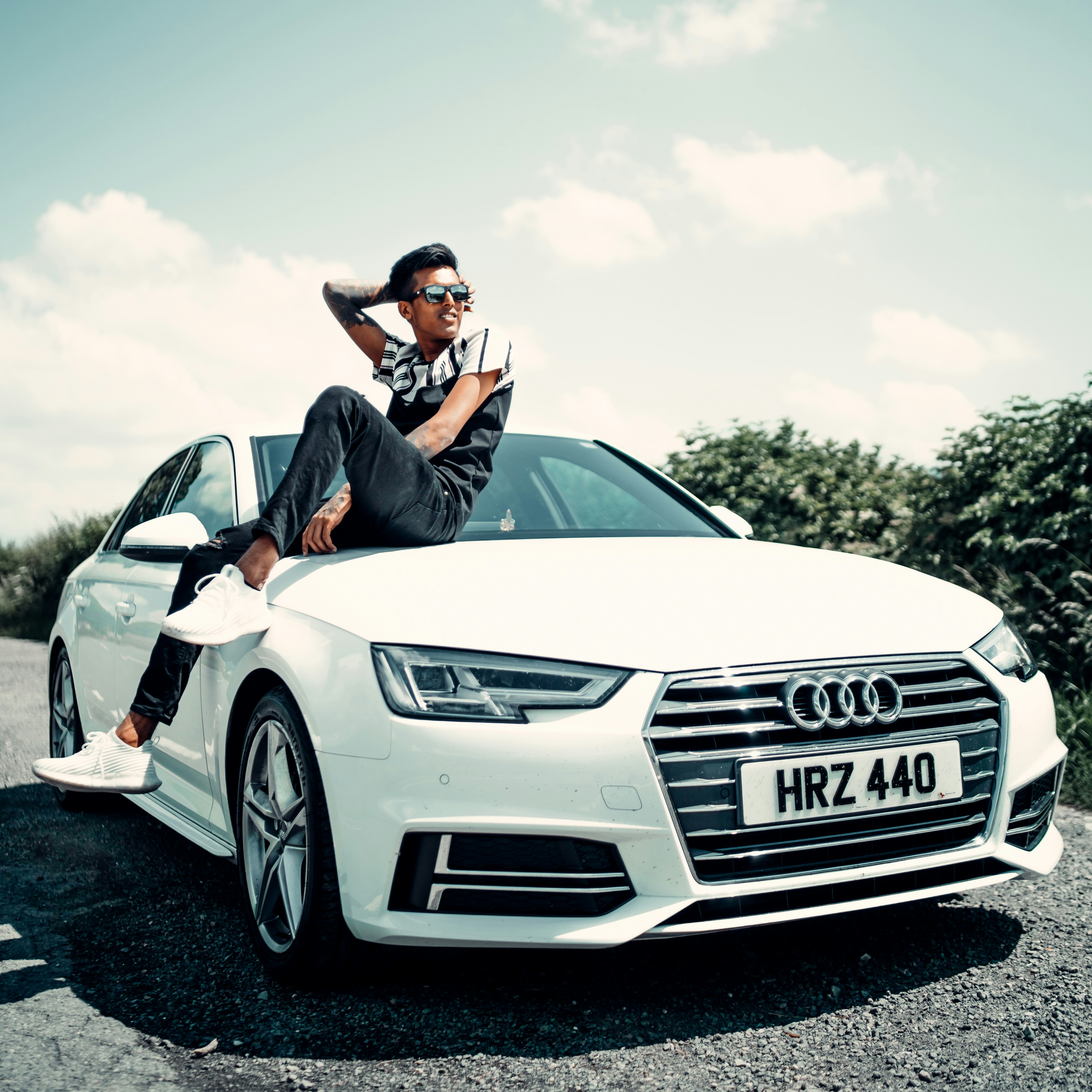 Swagger in the Sun: Man on the Hood of a White Audi